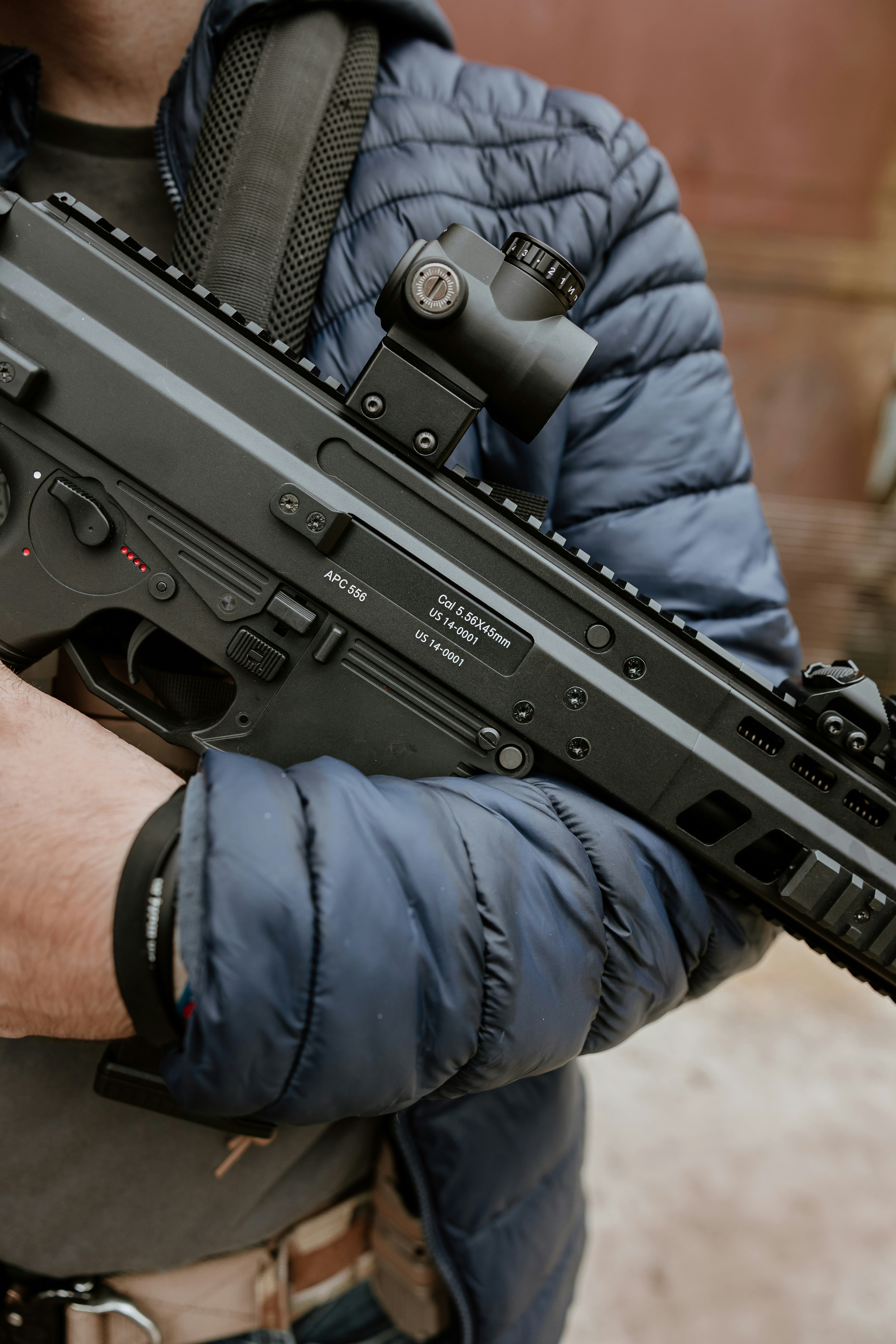 Close-armed silhouette: the rifle tucked under a puffer-warmed arm