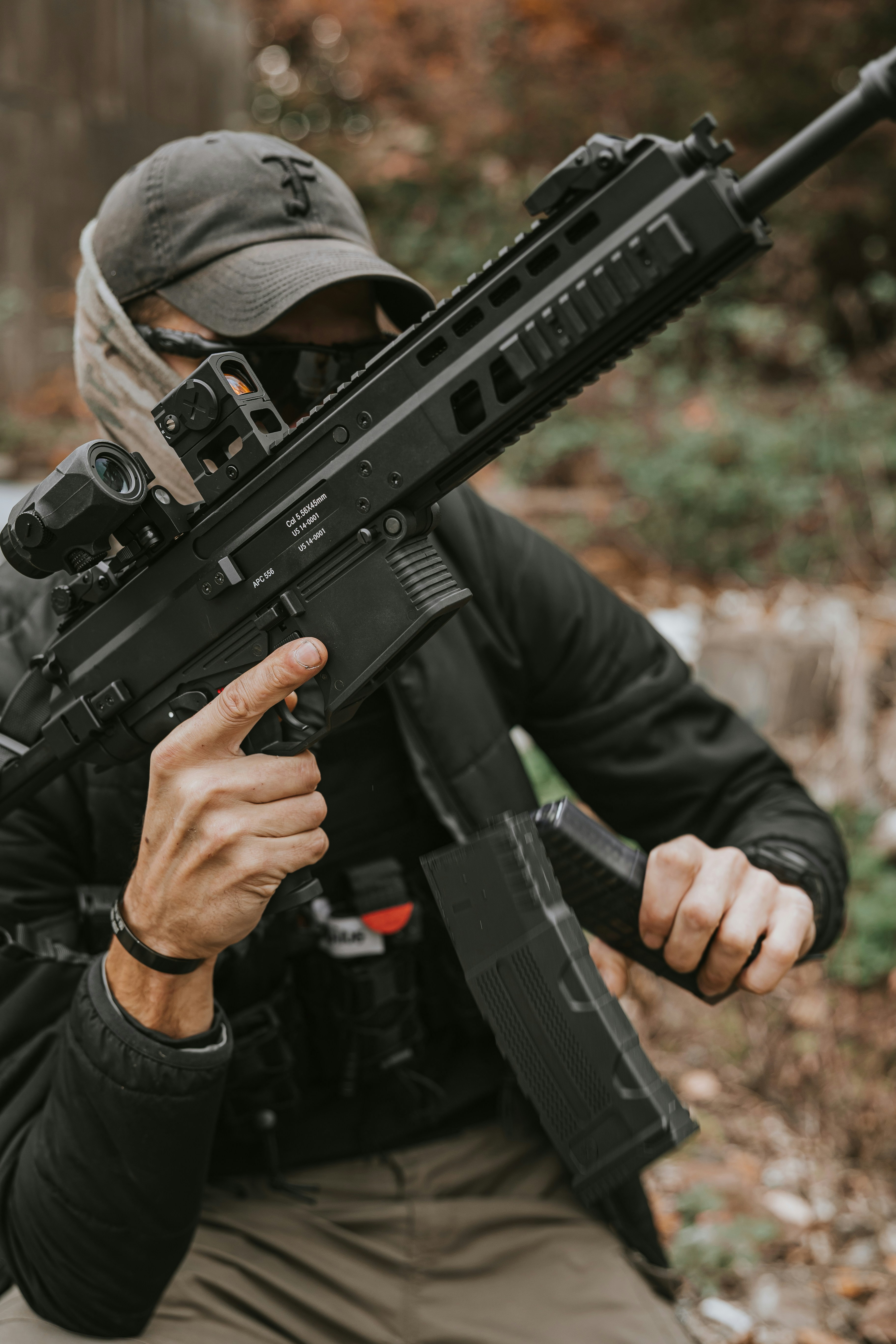 Masked marksman with a high-rail rifle in a forested backdrop