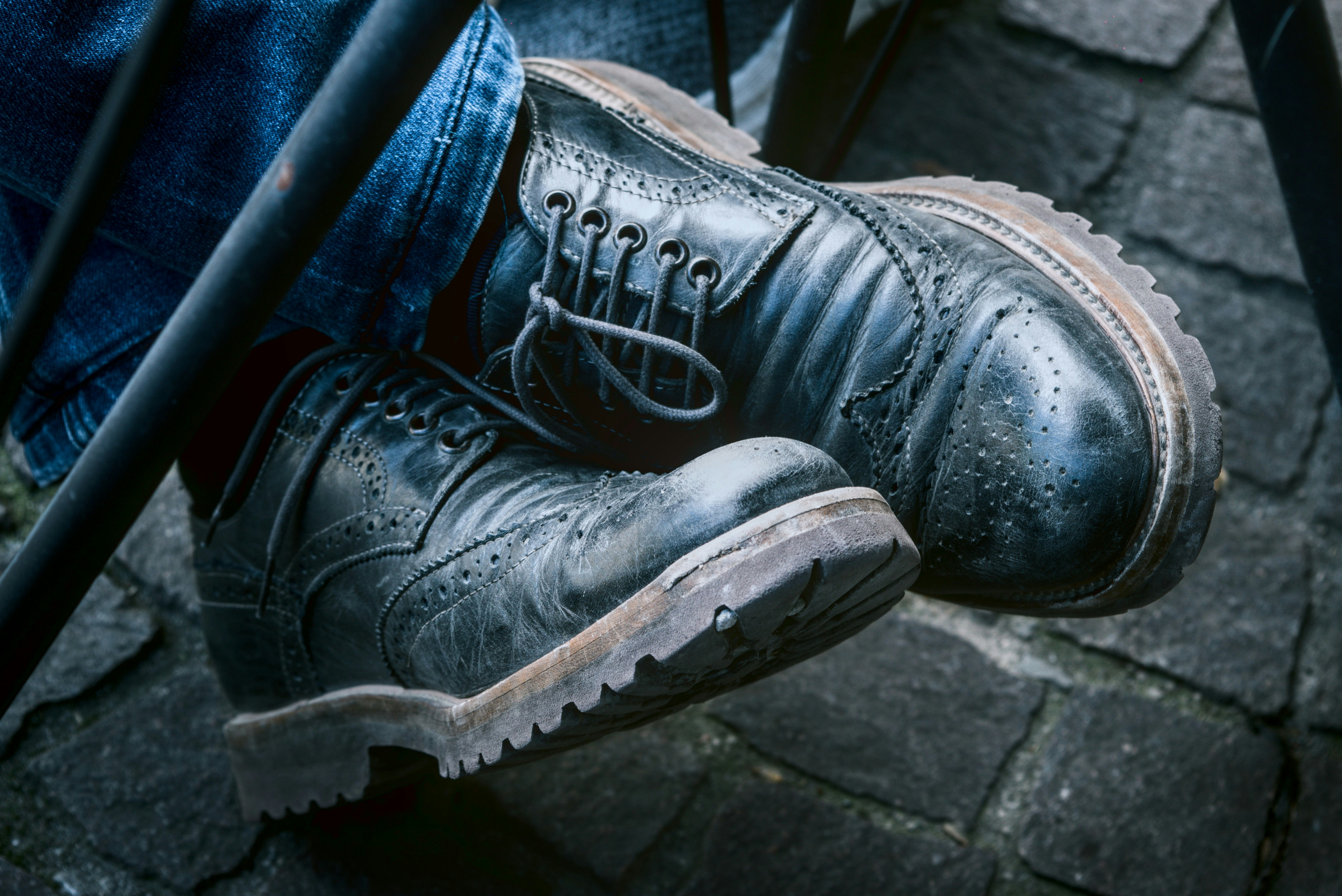 Weathered Combat Boots Resting on Wet Cobblestones
