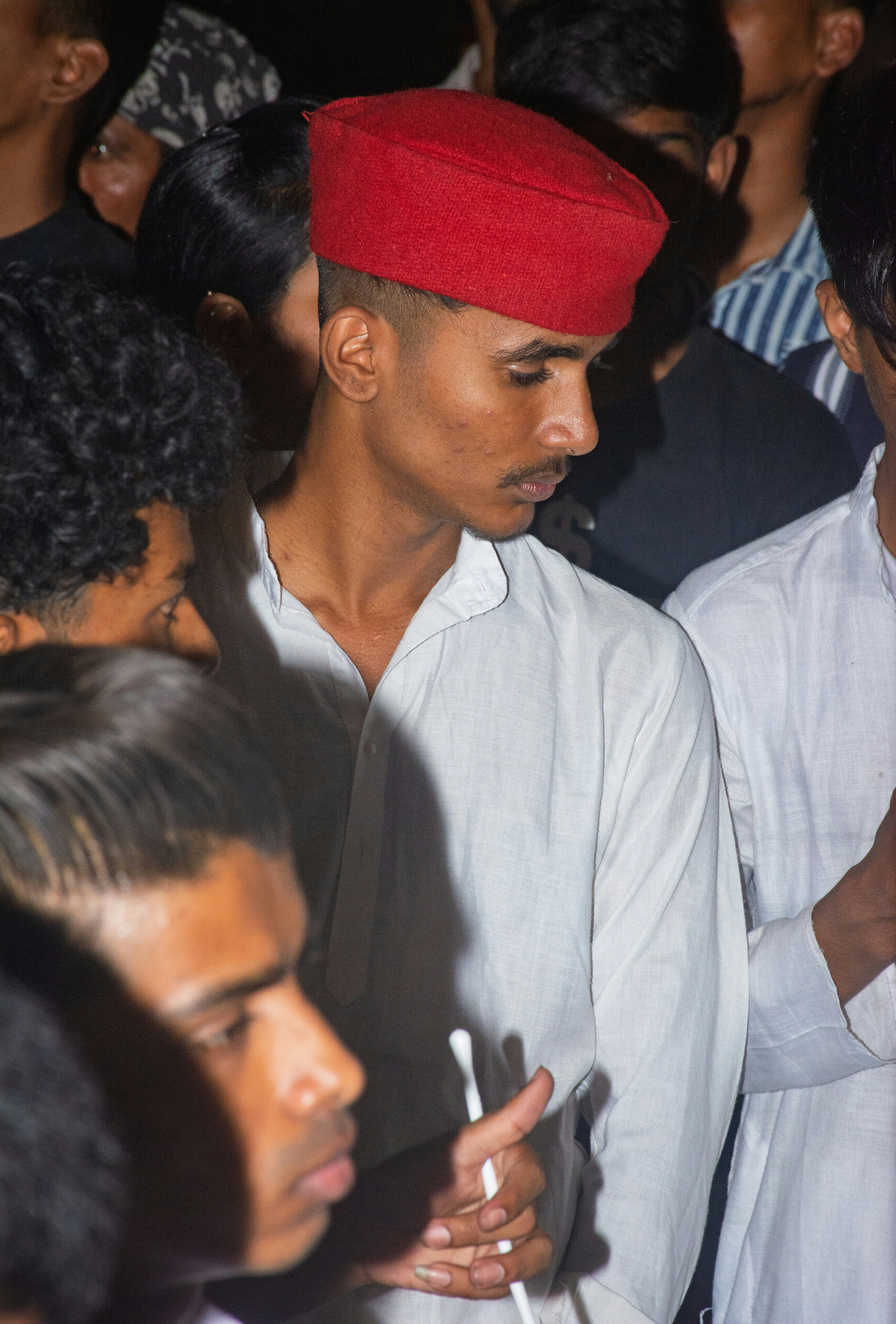 A Red Turban Silhouette: Focused Gaze Amid Crowded Night