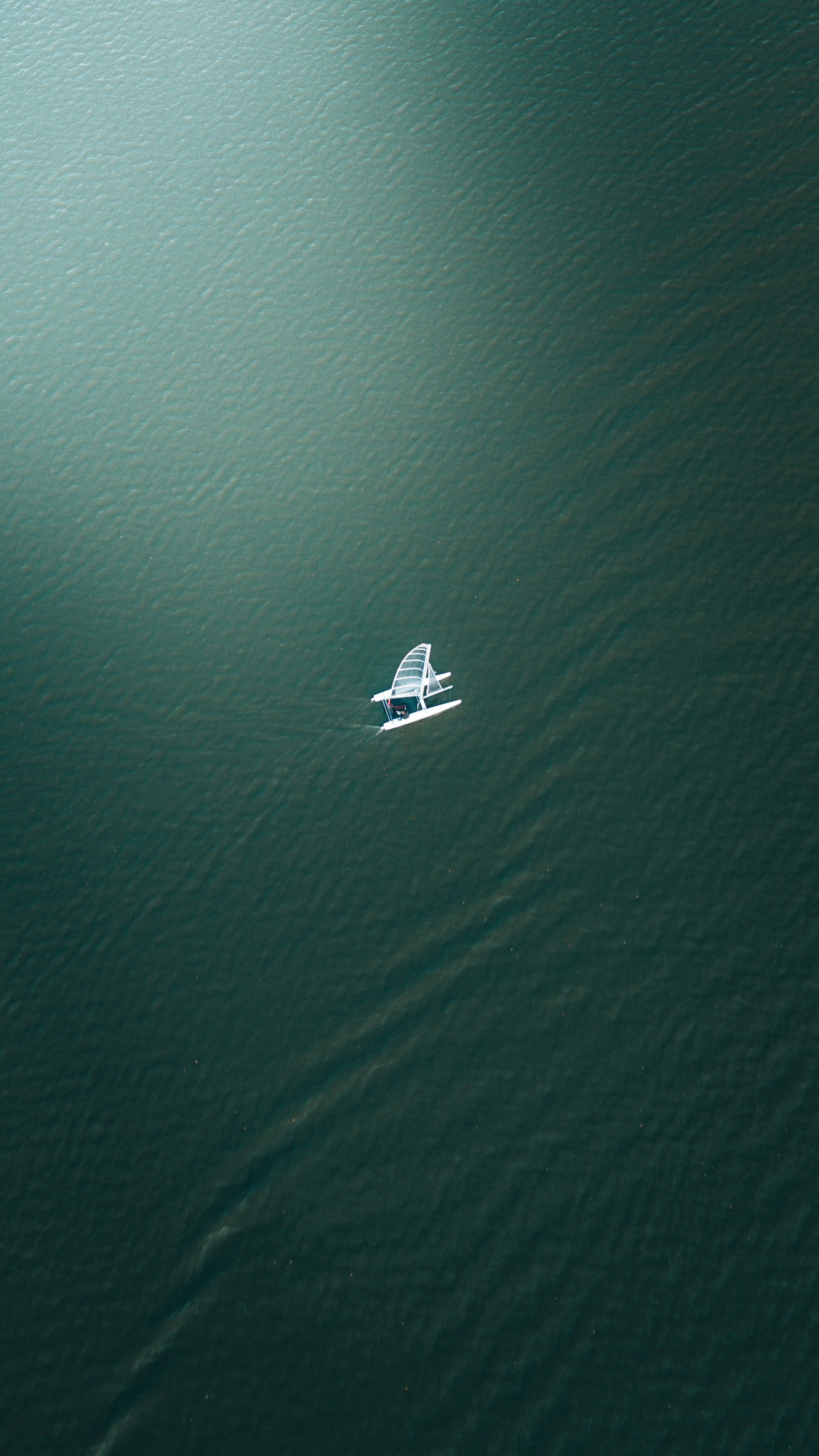 Sailboat Trace: A lone sailboat drifts across emerald waters