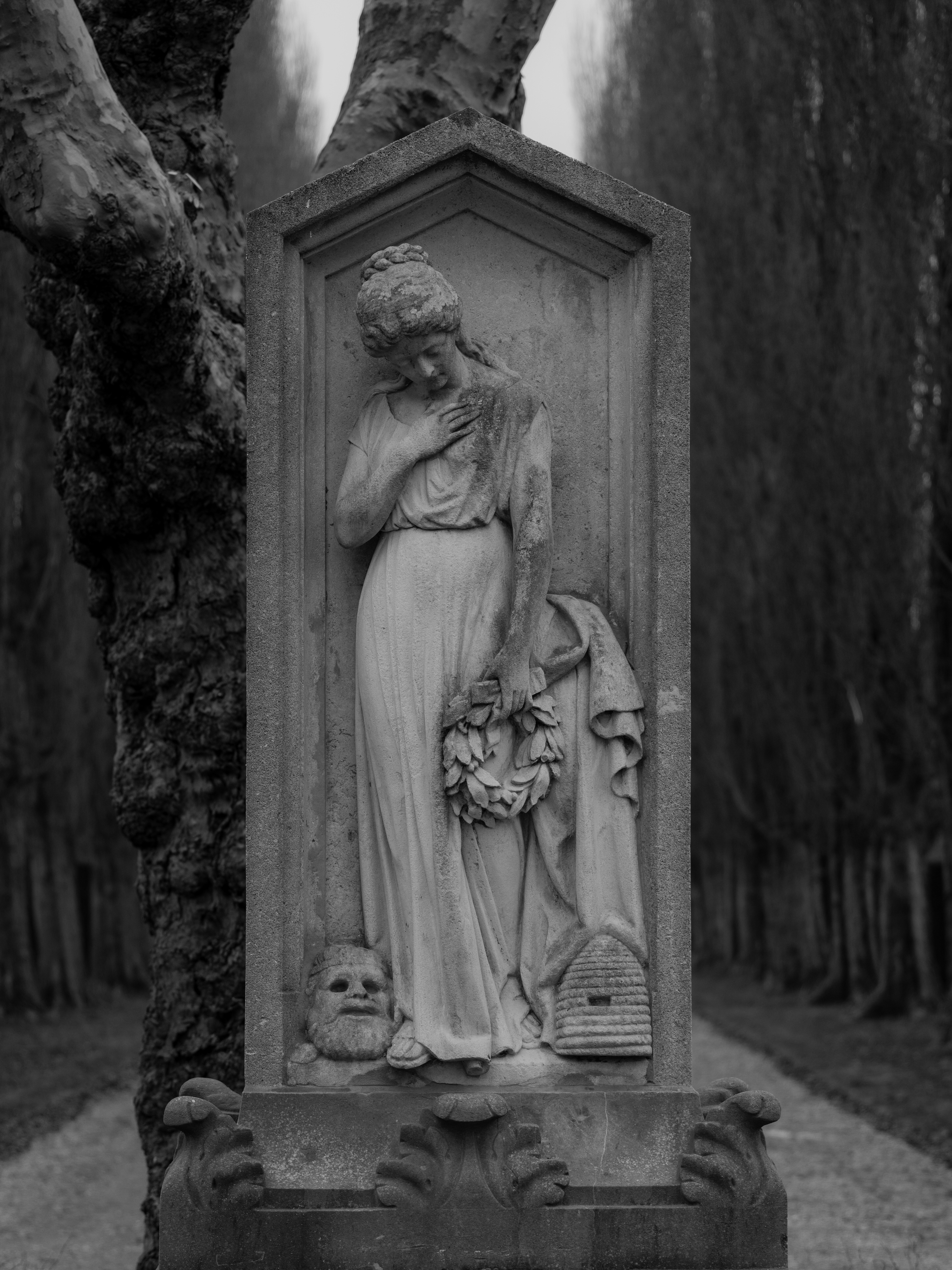 Silent Guardian in Stone: A Grave Statue Framed by Narrow Pathways