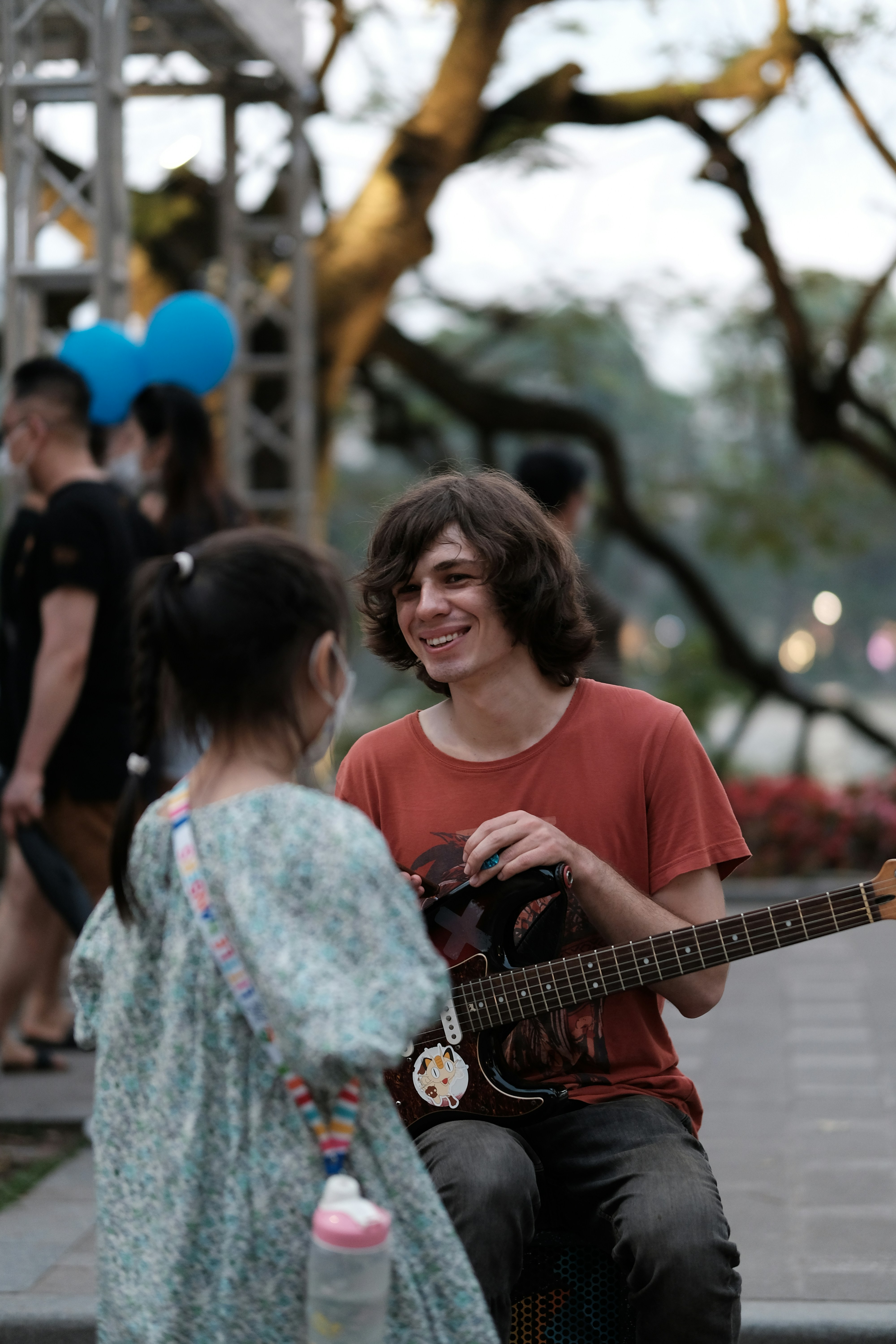 Guitarist in a Parkful Moment: Friendly Exchange Under a Dappled Sky