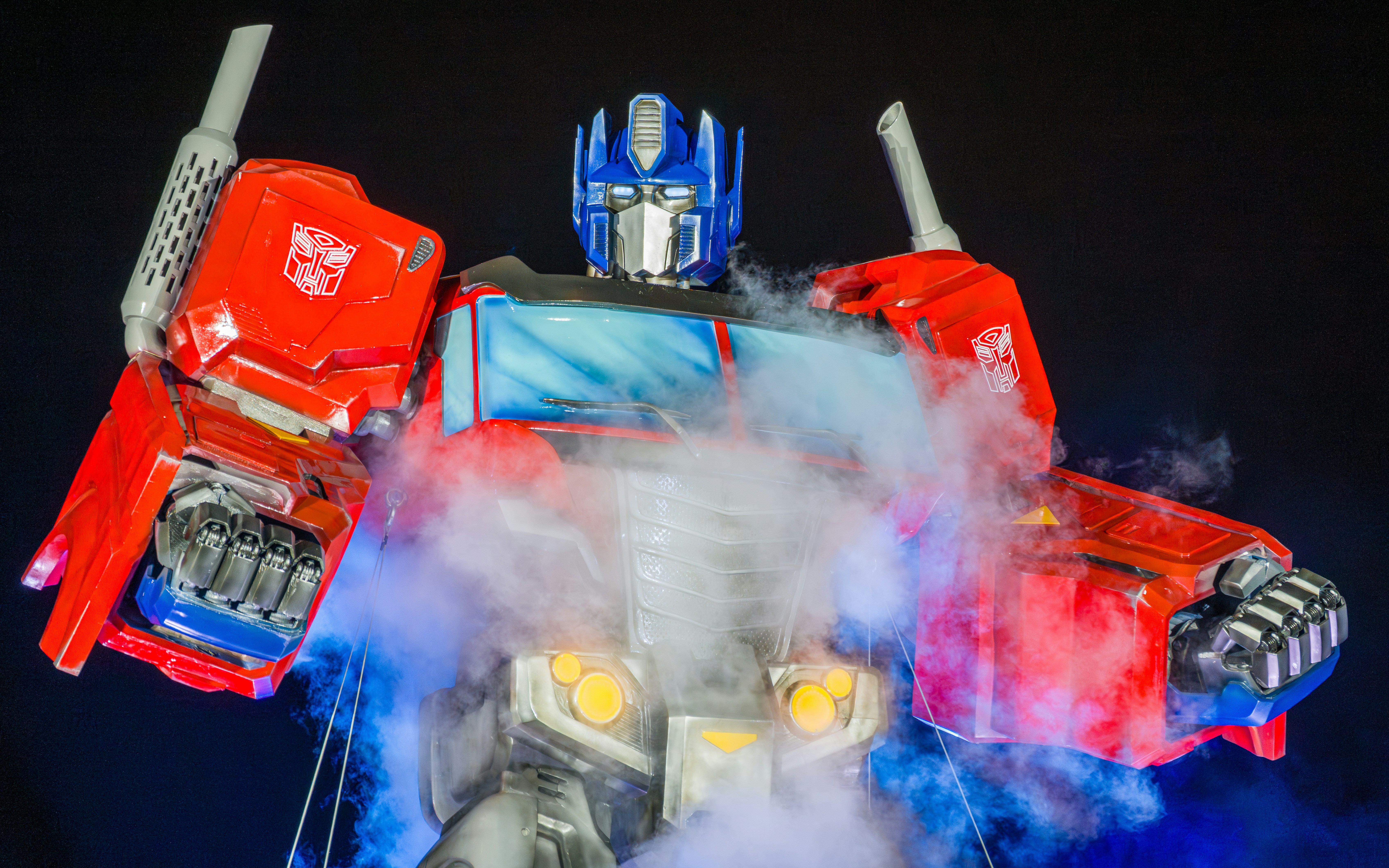 Neon-Red Sentinel: Optimus Transforms Under Smoke and Spotlight