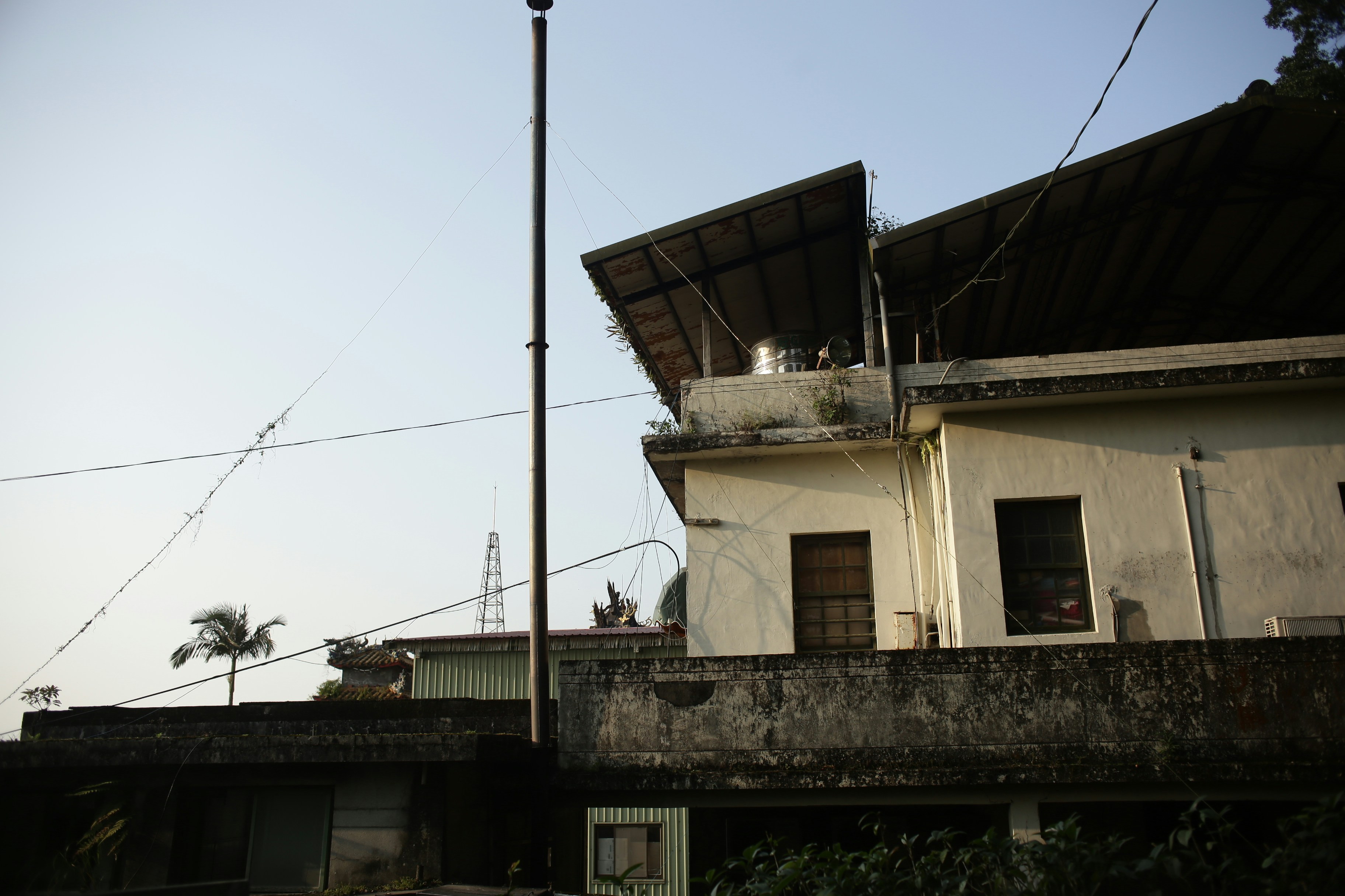 Sunlit rooftop facade with weathered concrete and a tilted roof