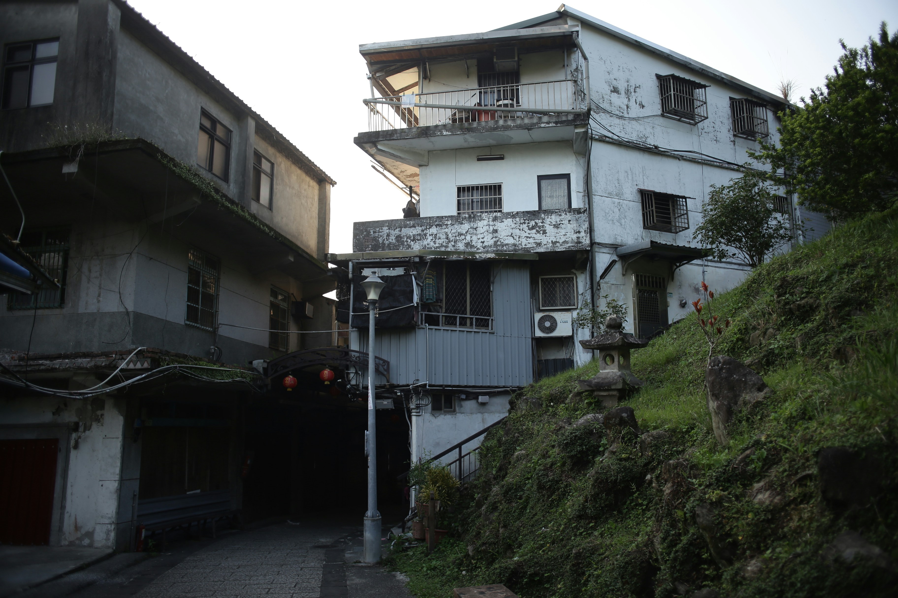 Weathered apartment stack perched above a mossy incline