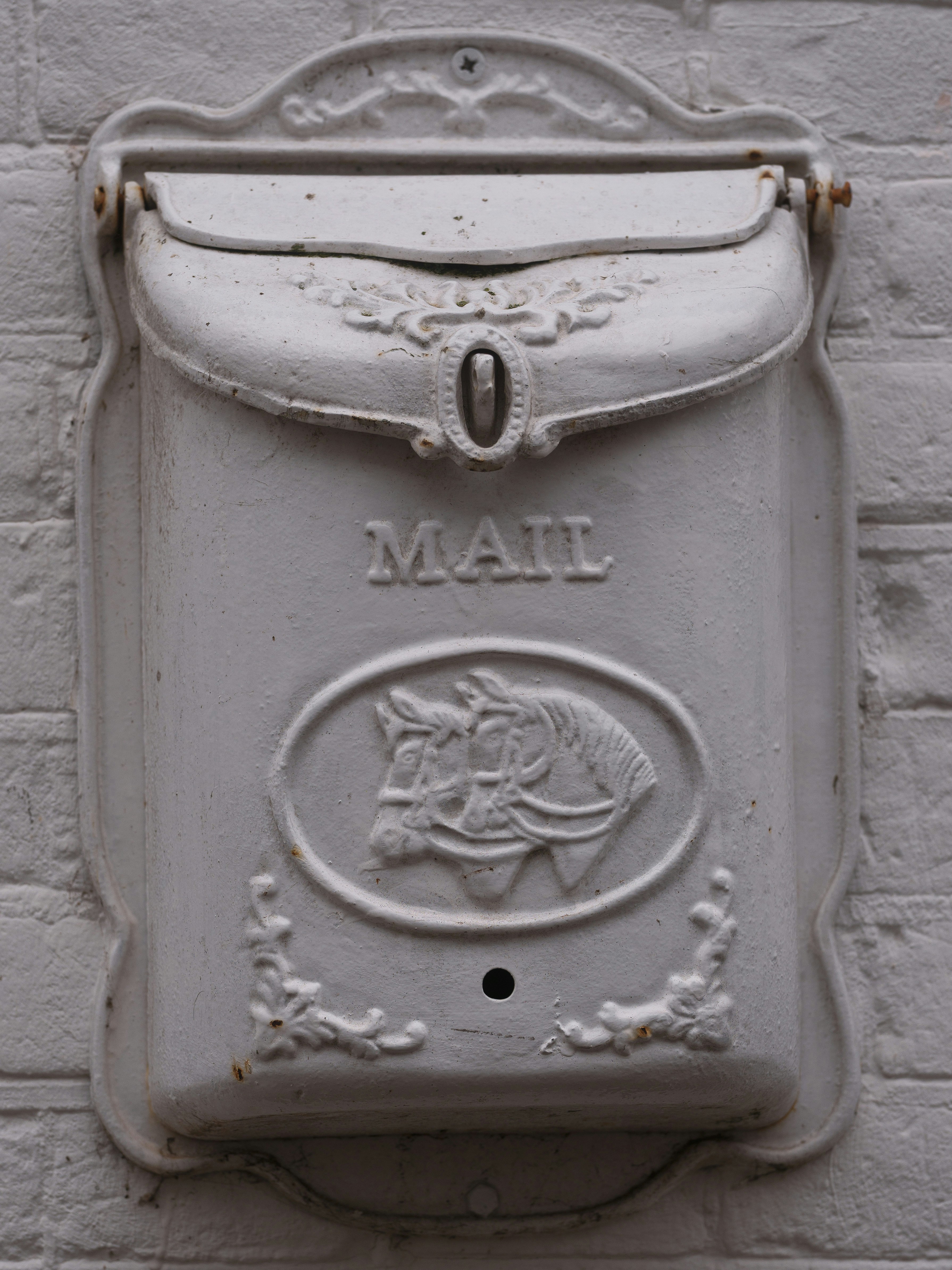 Weathered White Mailbox Carved with a Horse Emblem