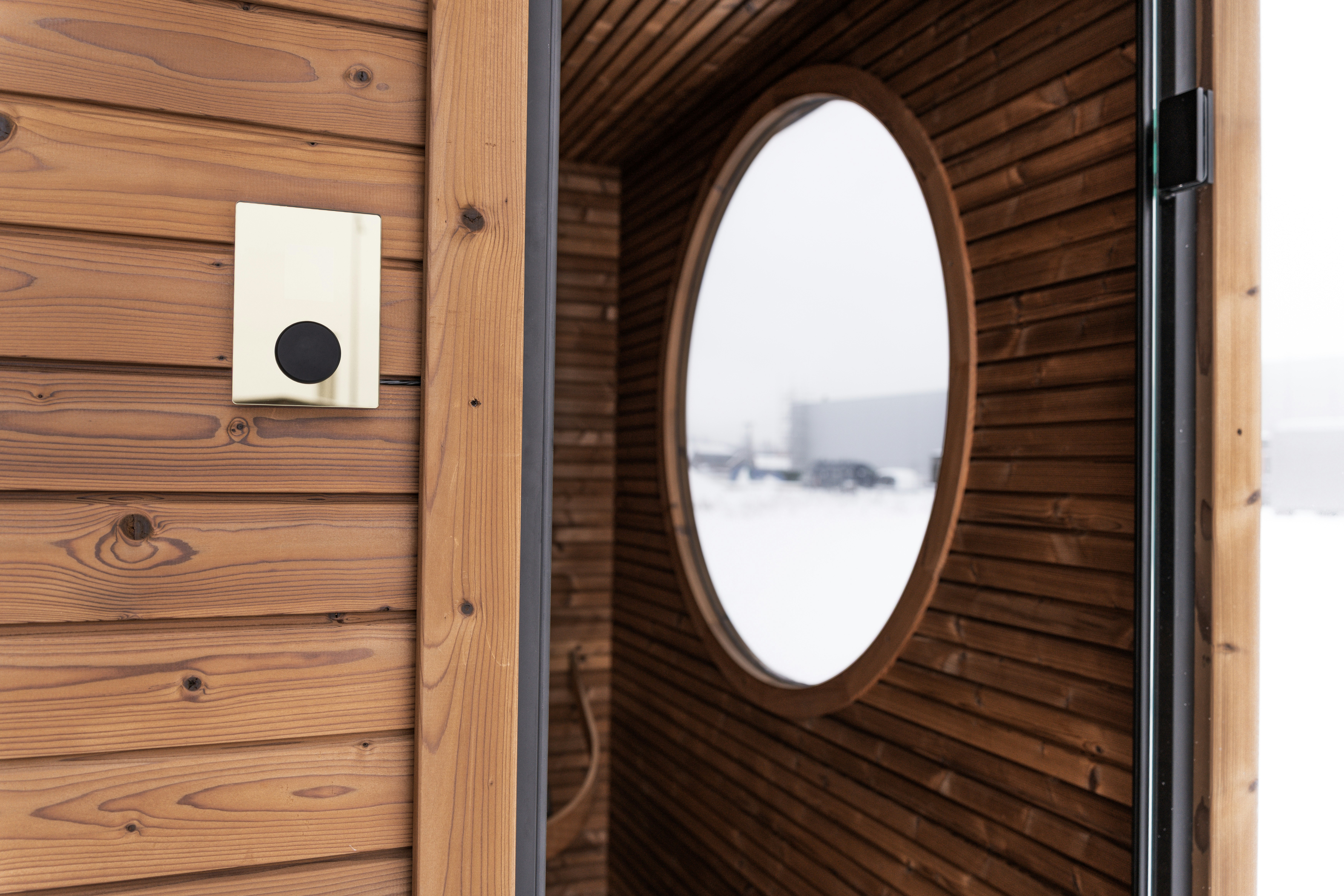 Wooden Cabin Entrance with Oval Window and Snowy Backdrop