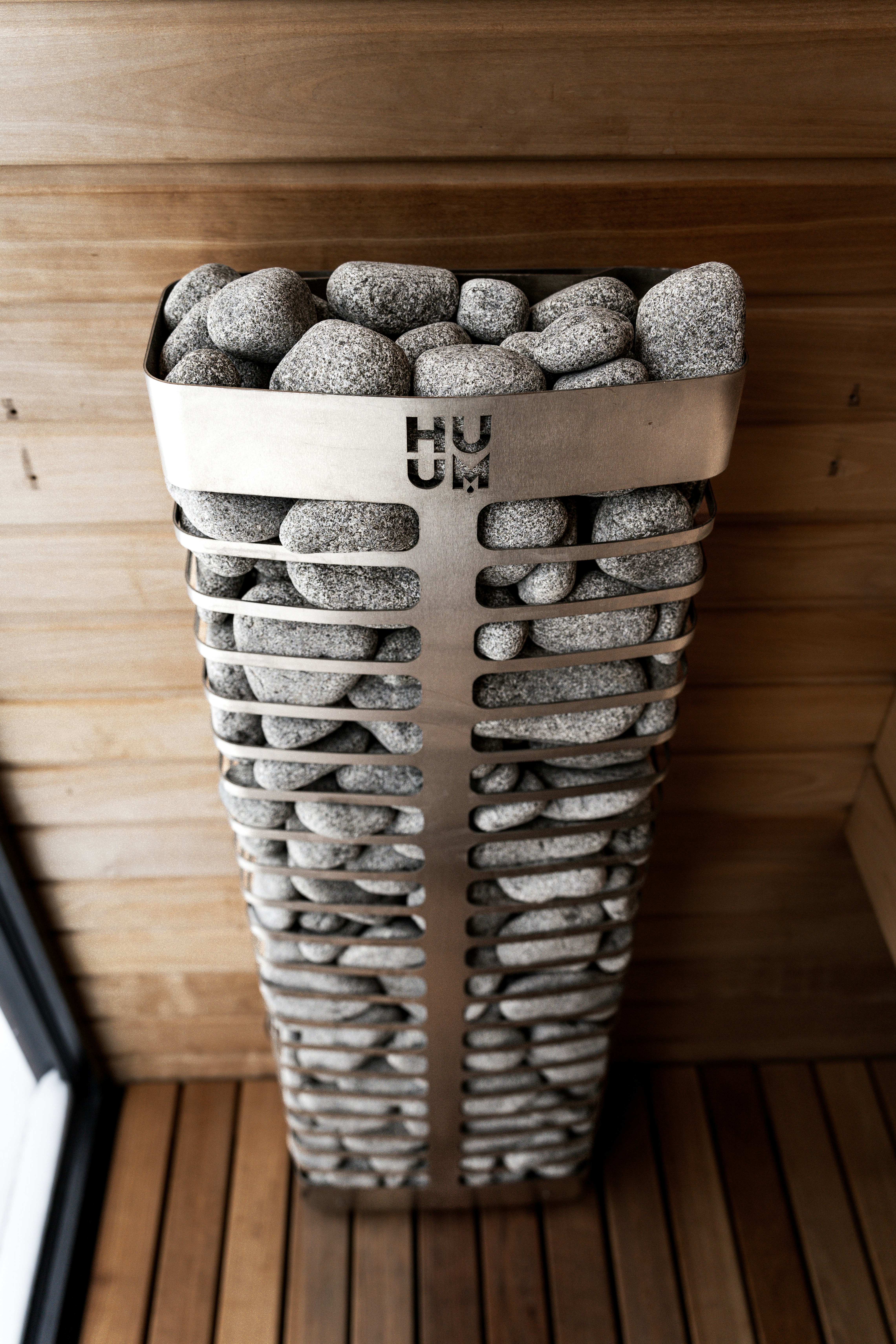 Stone-filled sauna basket rising from wooden interior
