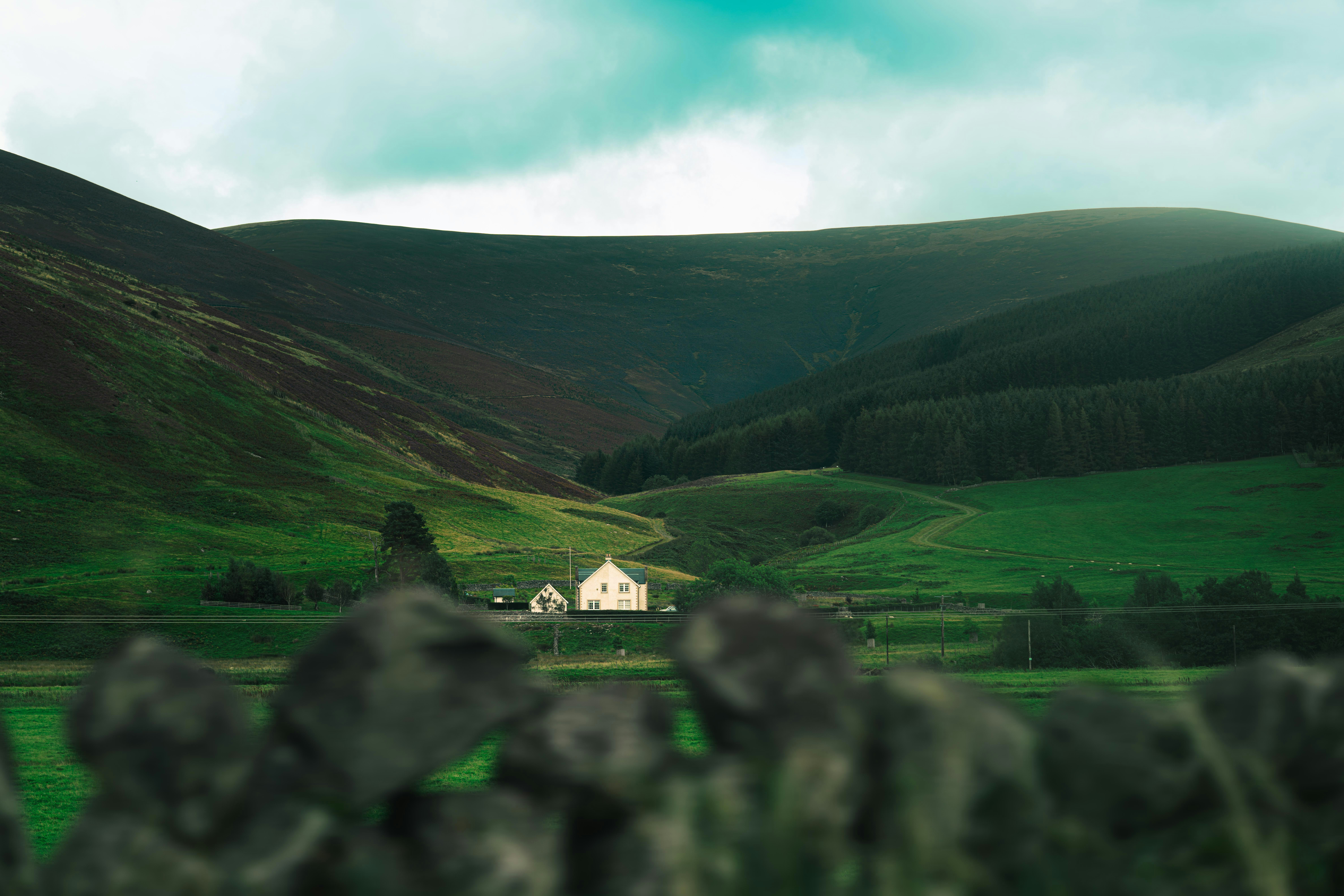 White farmhouse at the base of rolling green hills