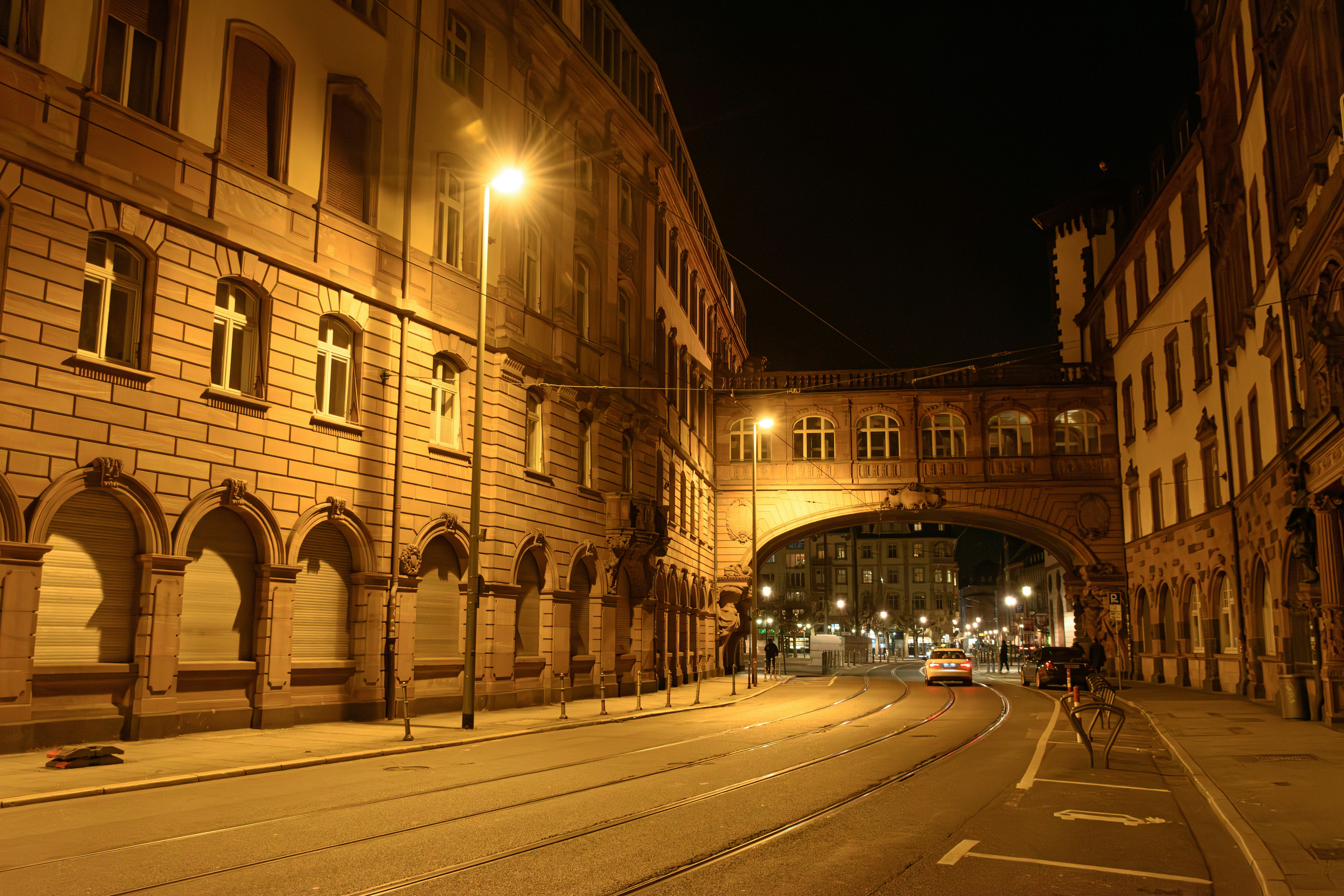 Night-time Boulevard Under Passage: Streetlights, Trams, and Historic Facades