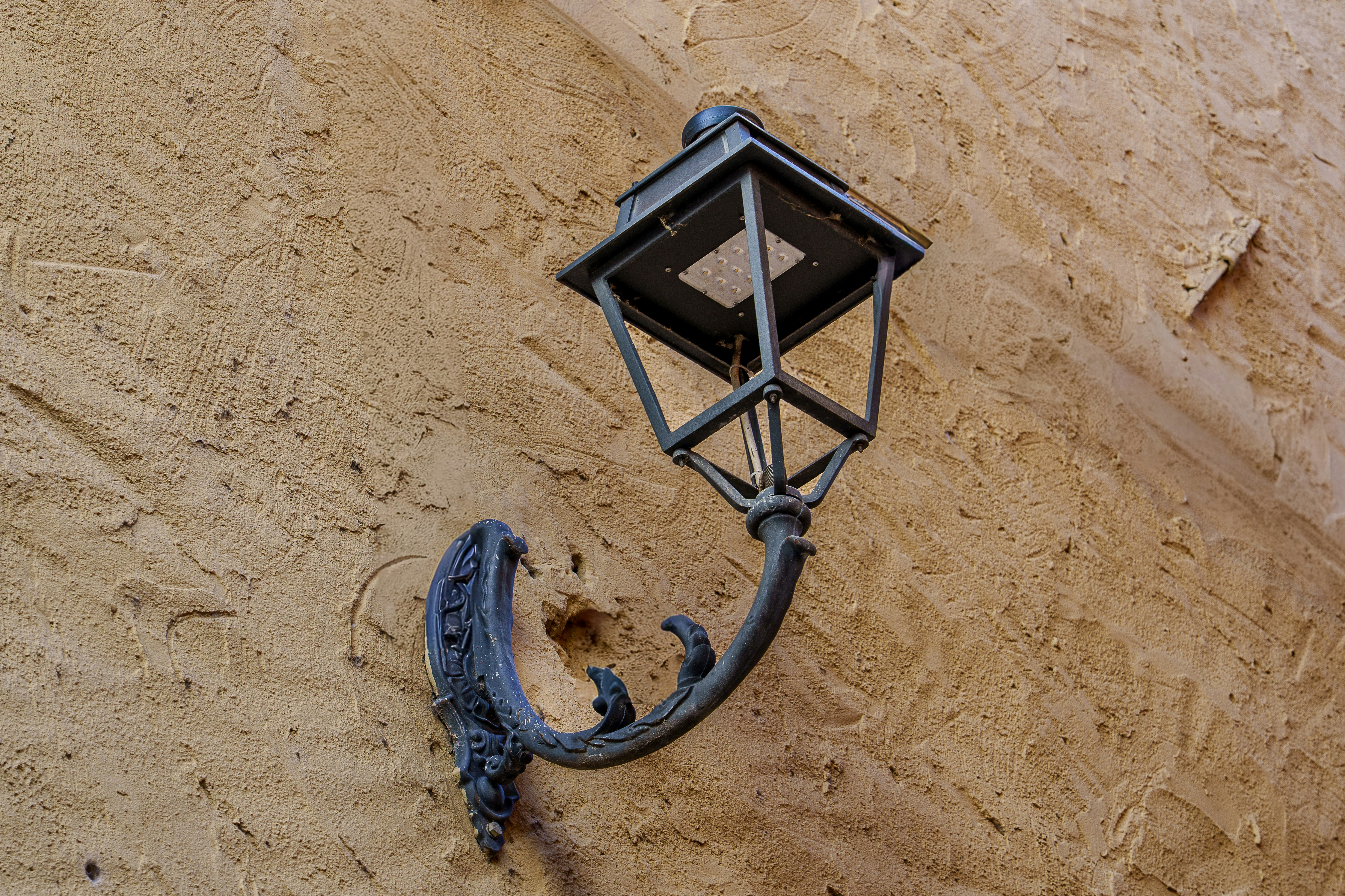 Ornate lantern on sun-washed stucco wall