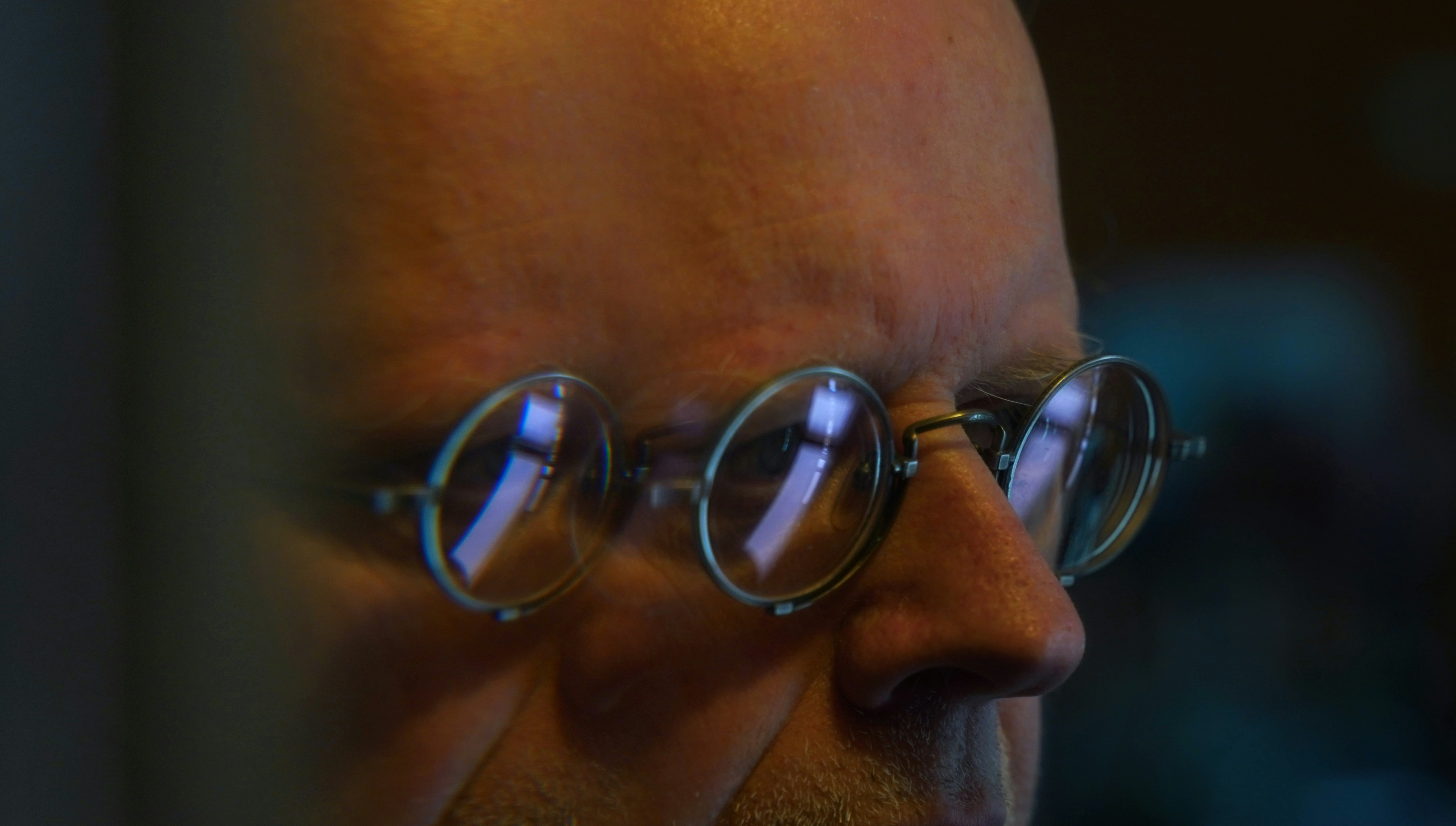 Close-up of a contemplative observer through round spectacles
