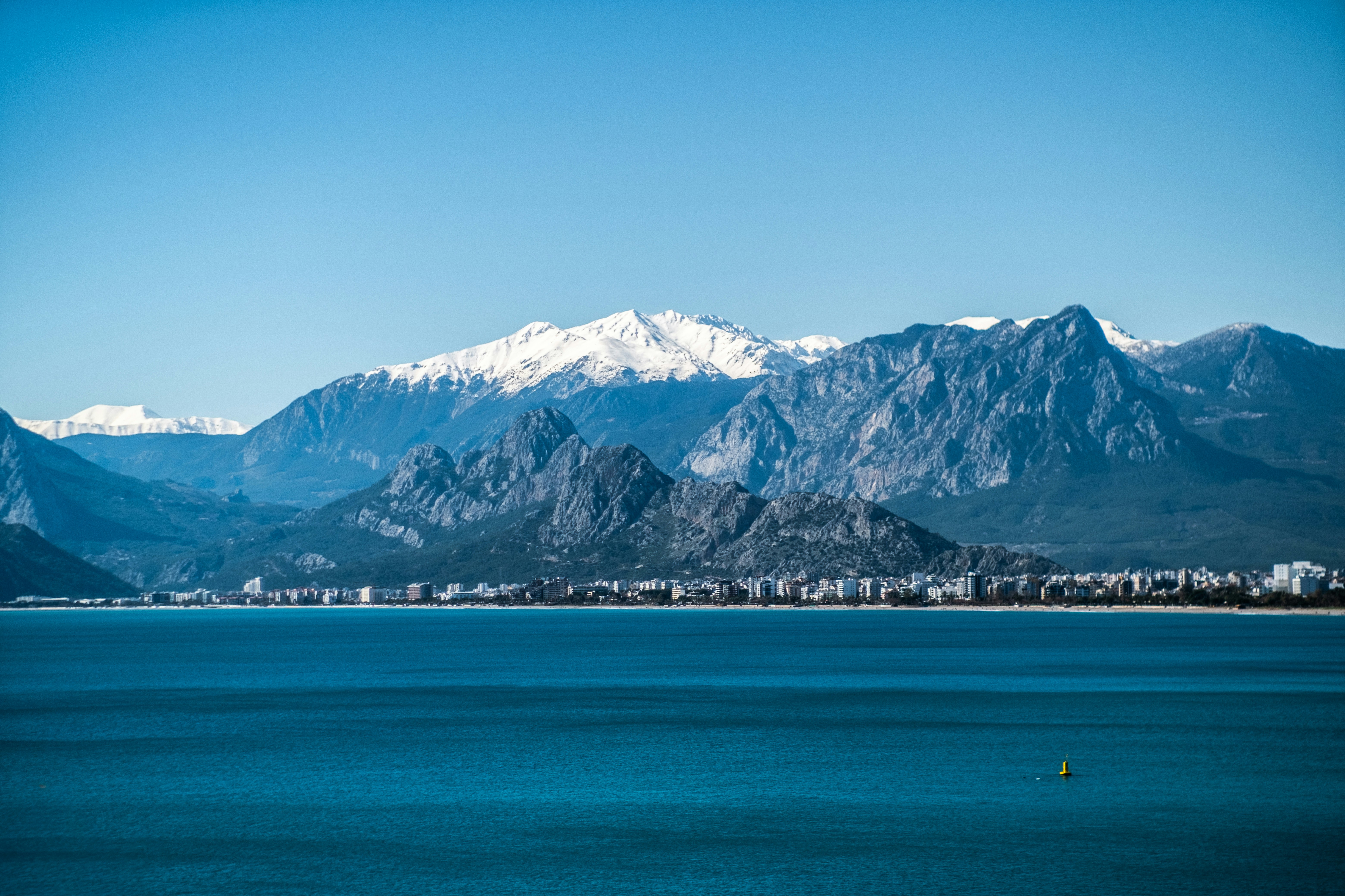 Snow-kissed Peaks Over a Coastal City