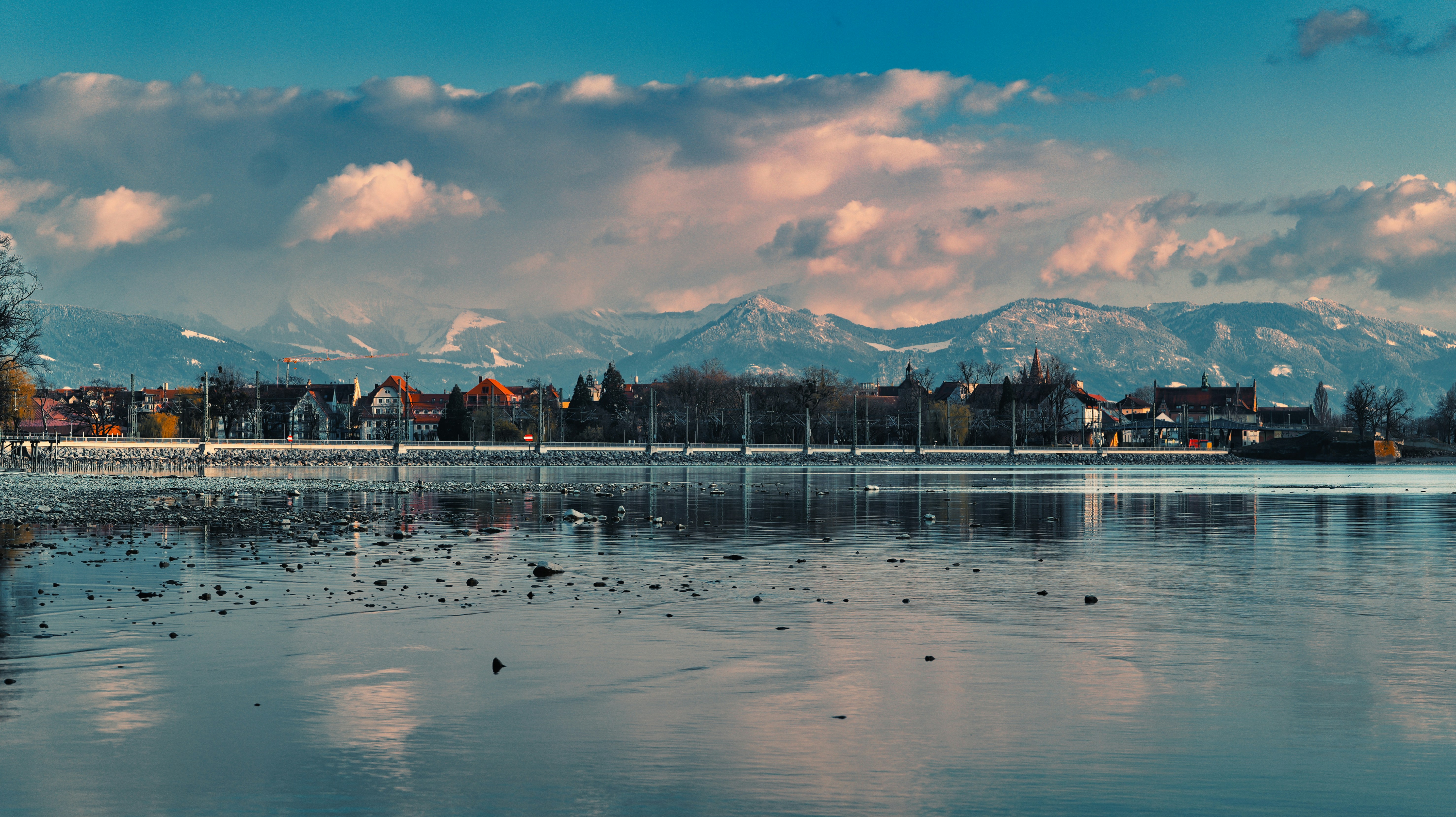 Bank of glassy water under pastel alpine skies