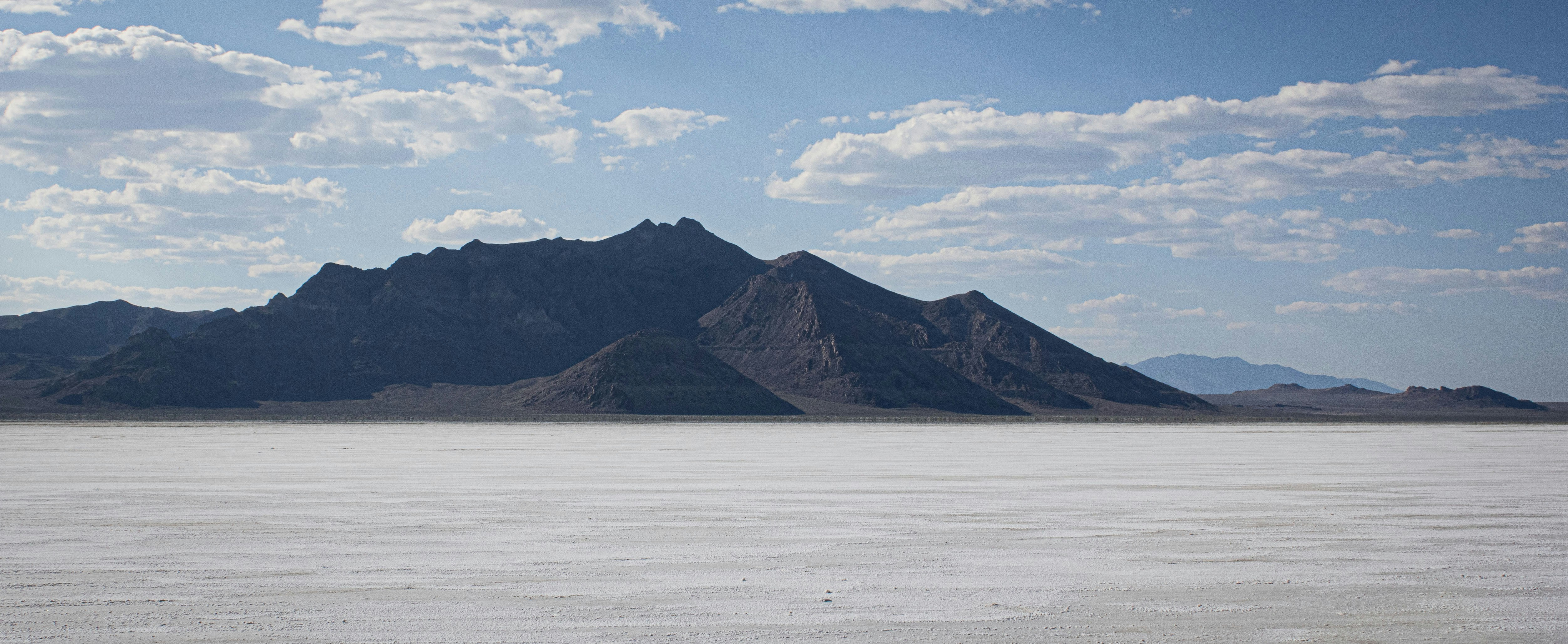 Deserted Salt Plain before a Jagged Mountain Range Under a Lattice of Clouds