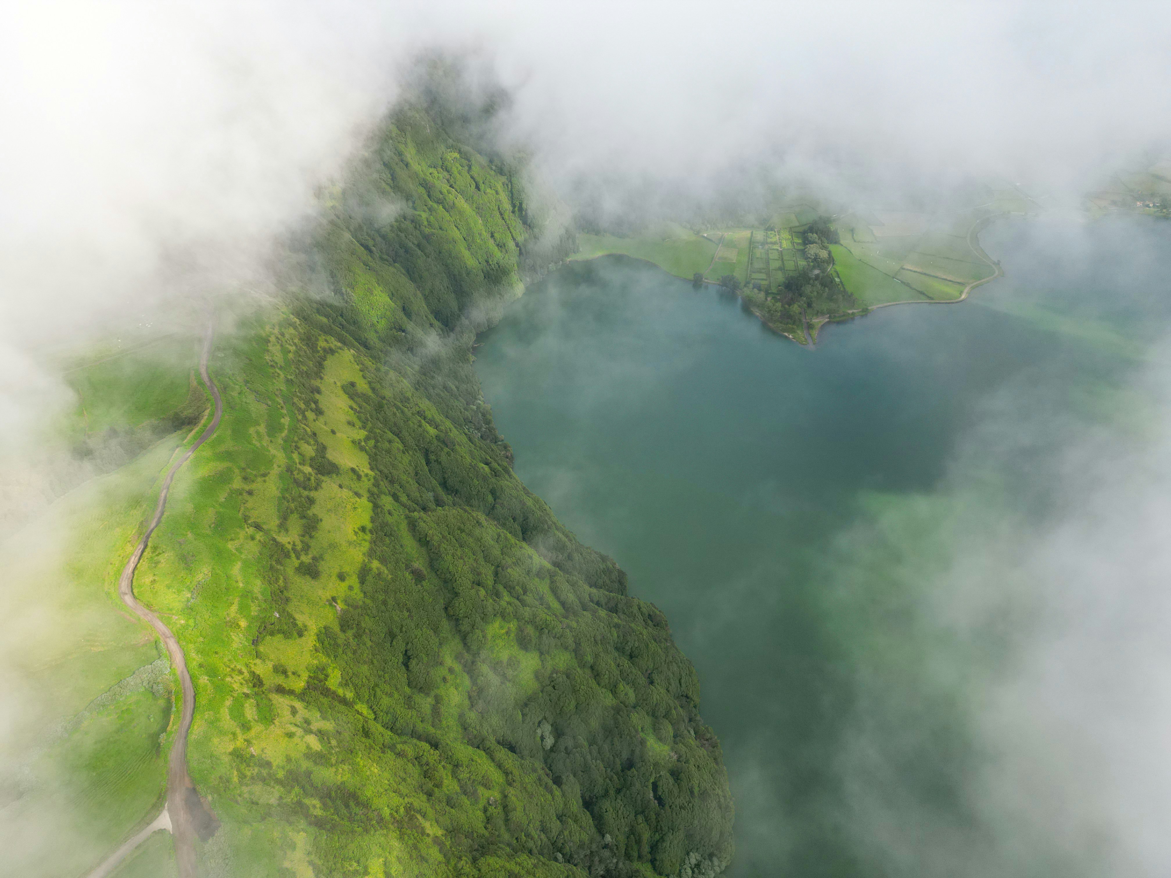Mist-veiled Rim: Aerial Calm Over a Verdant Reservoir