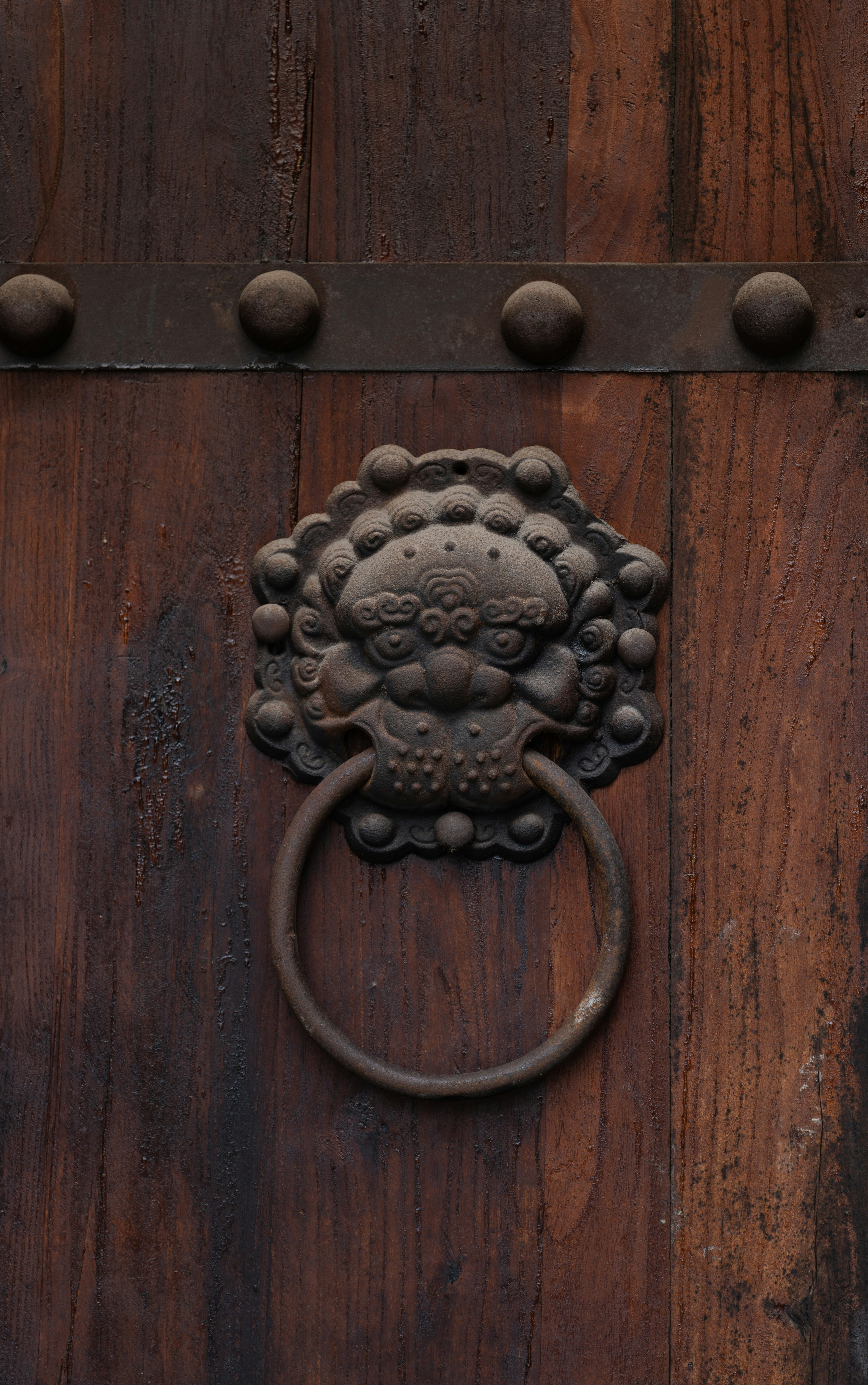 Ancient Door Knocker: Rustic Iron Guardian on Weathered Timber