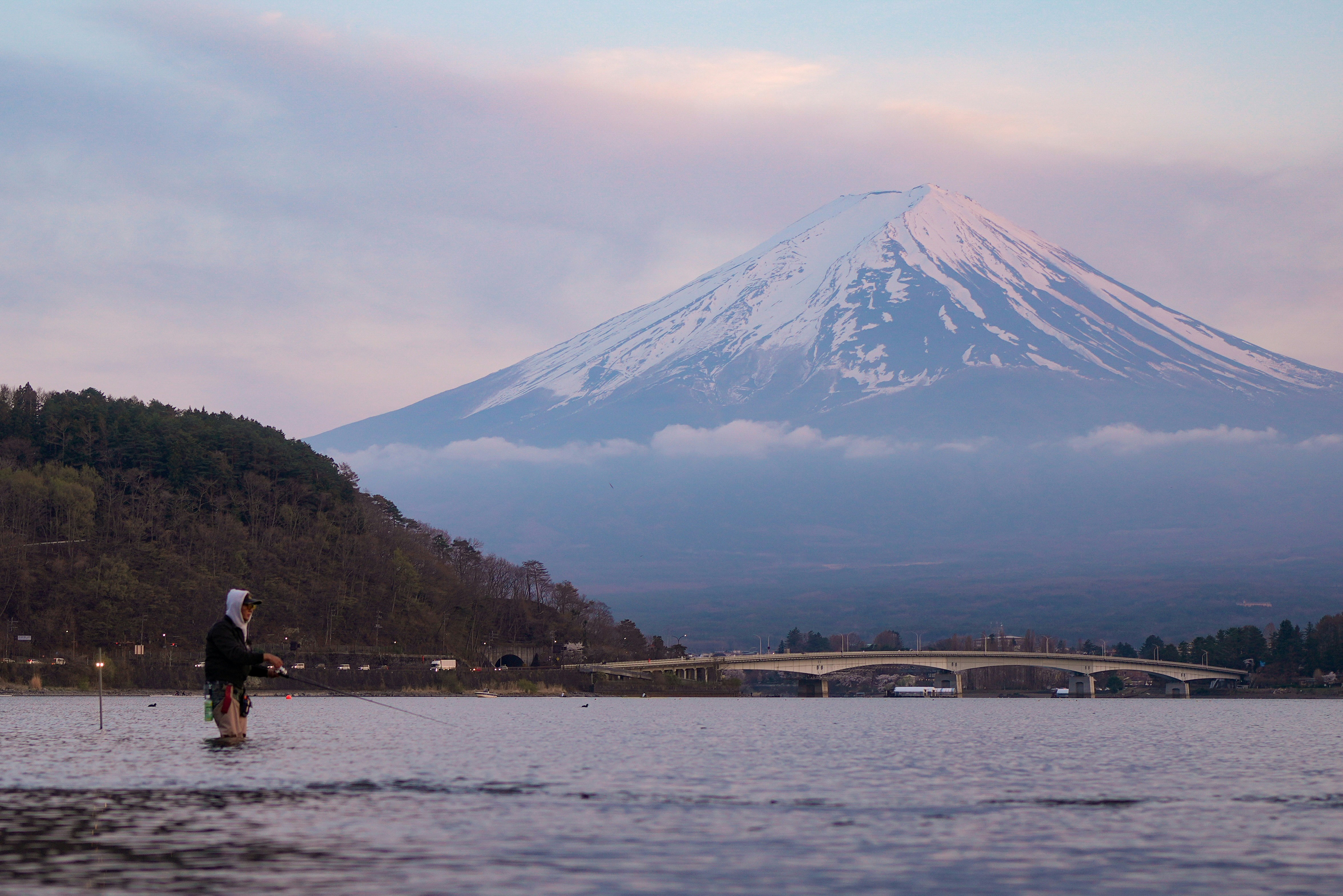 Mt. Fuji in calm waters: a lone angler by the lake at dusk