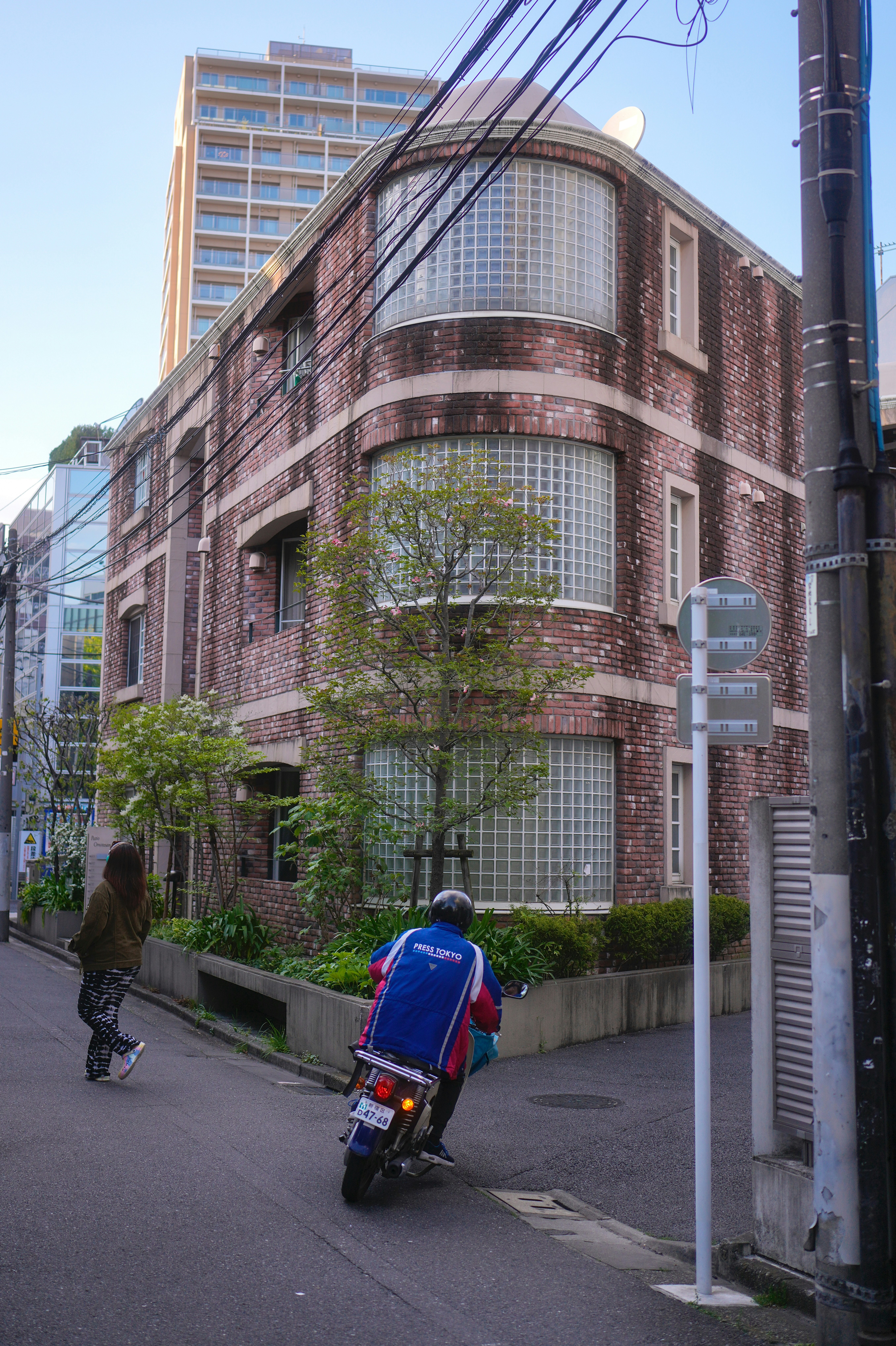 Motorbike turns a corner by a brick corner building under overhead cables