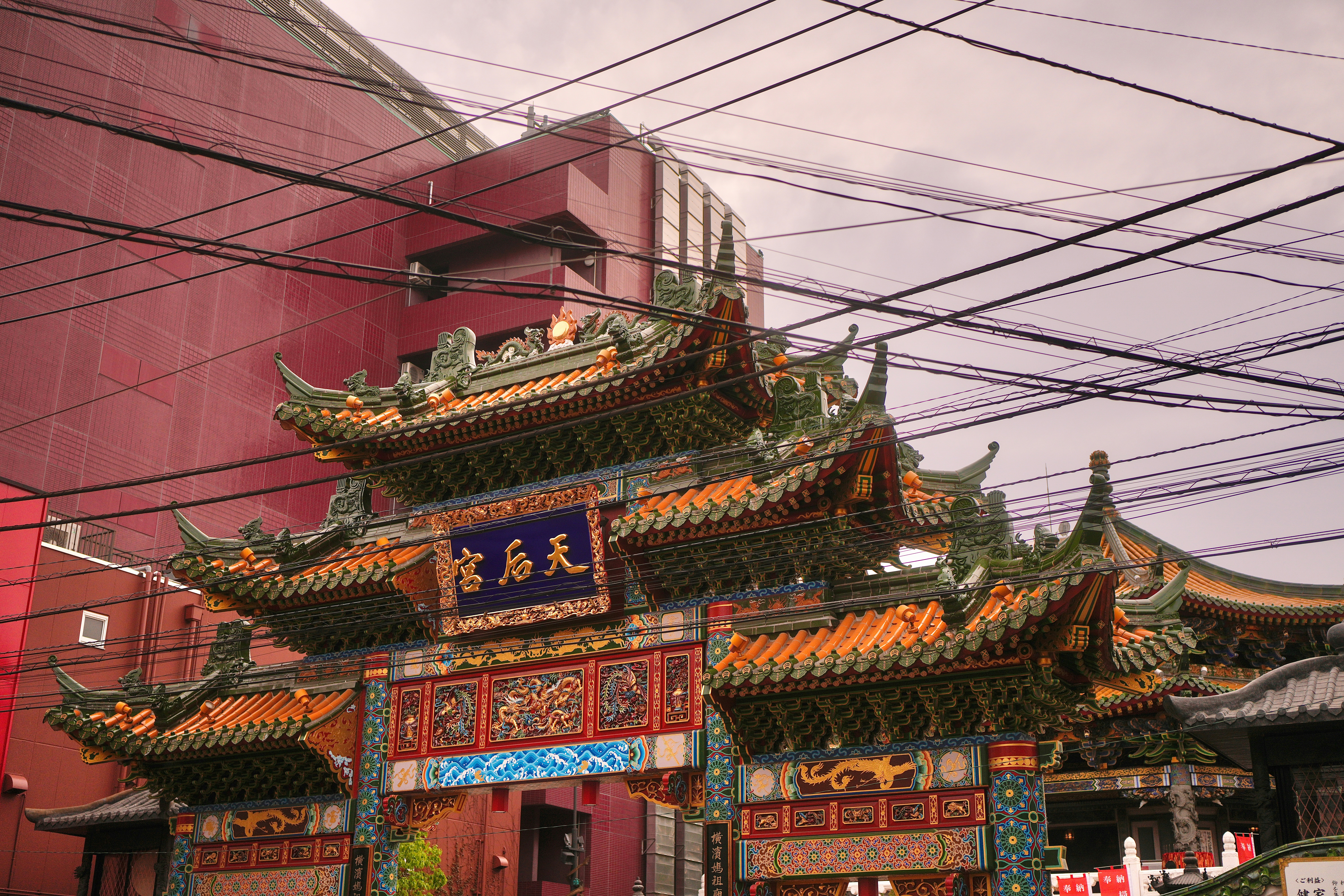  gateway with ornate temple doors under a tangle of urban wires