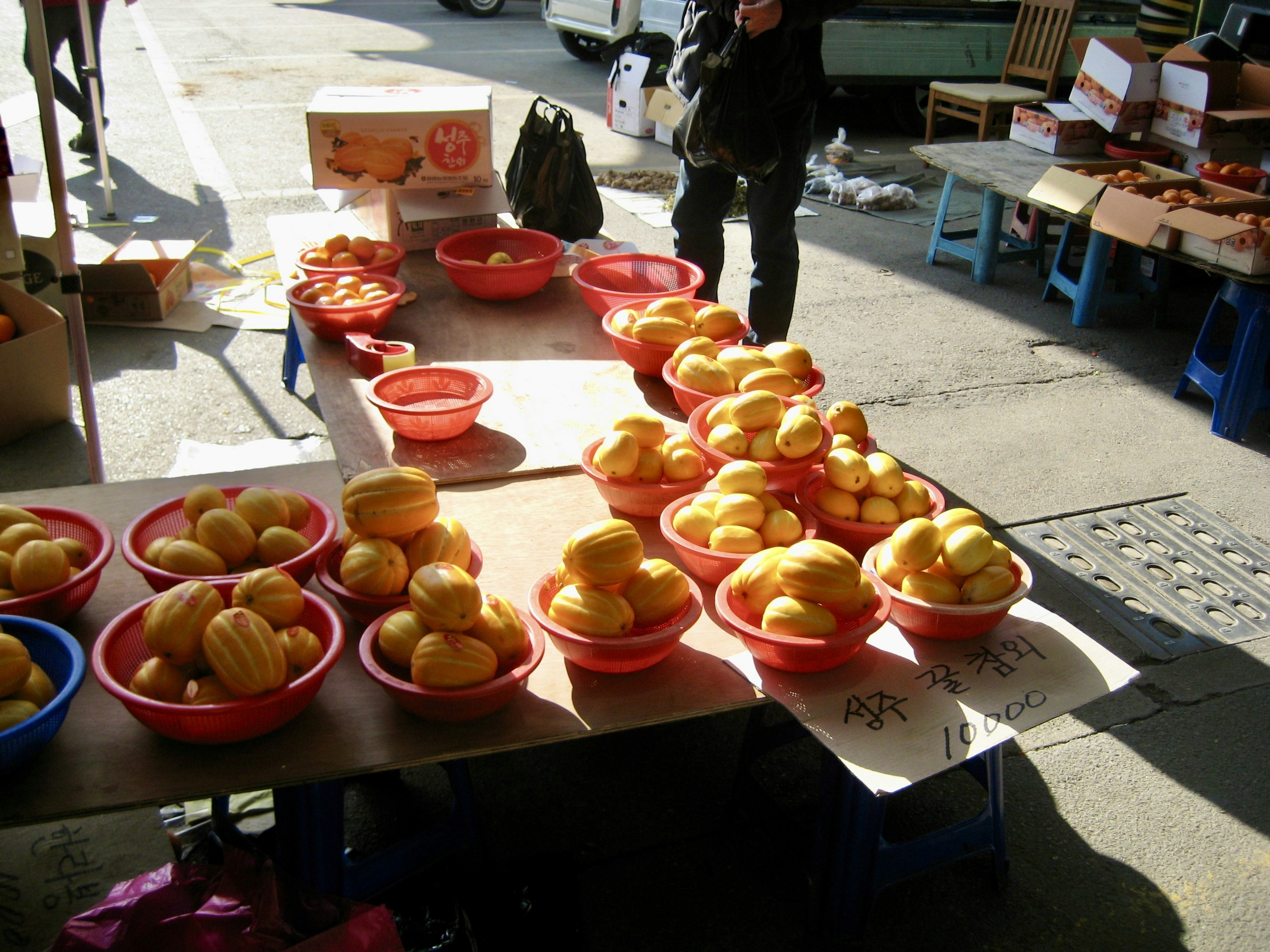 Sunlit Market Stacks: Melons and Tomatoes on a Busy City Stand