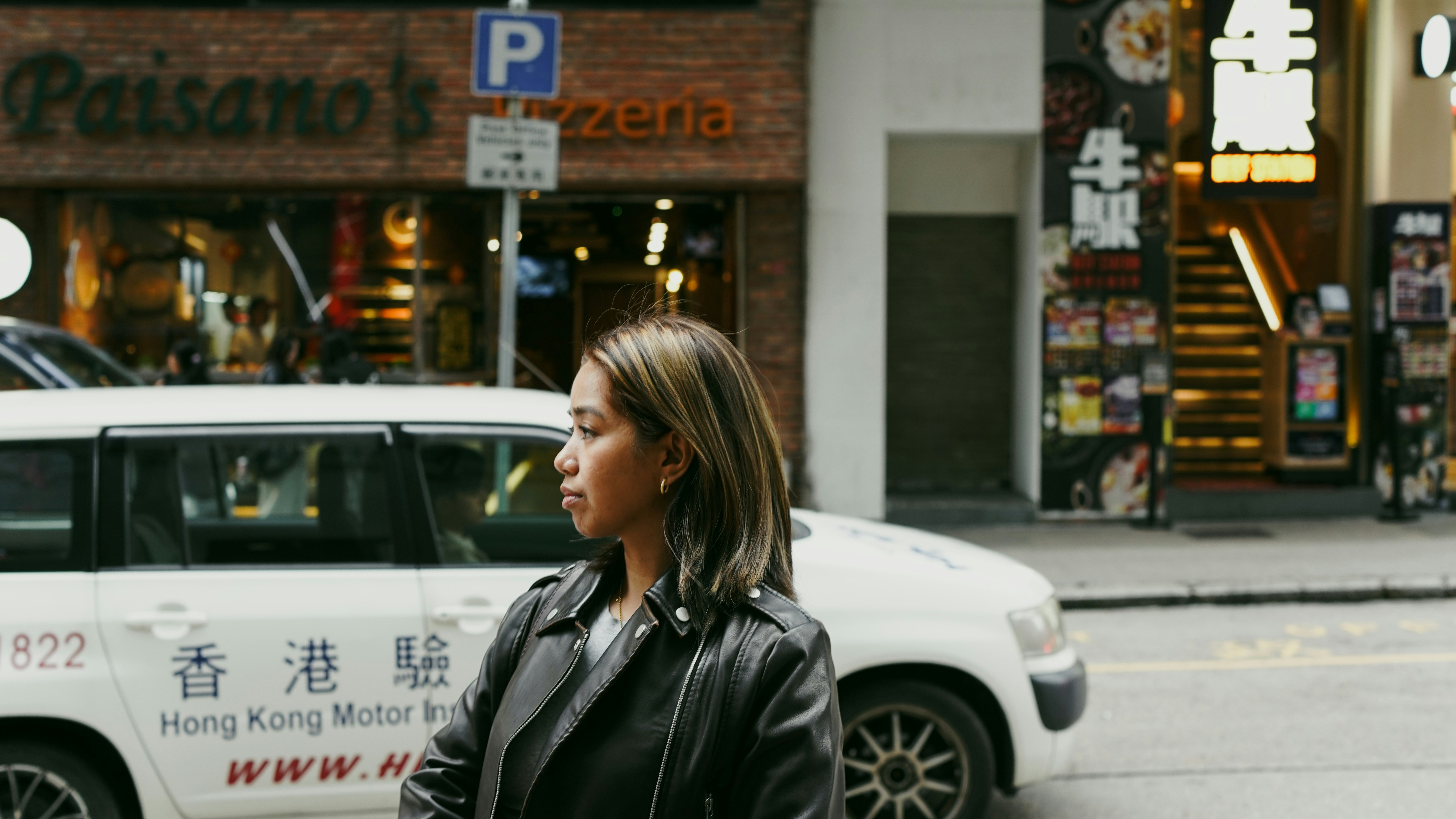 City Street Portrait: Quiet Gaze Amid Neon and Cars
