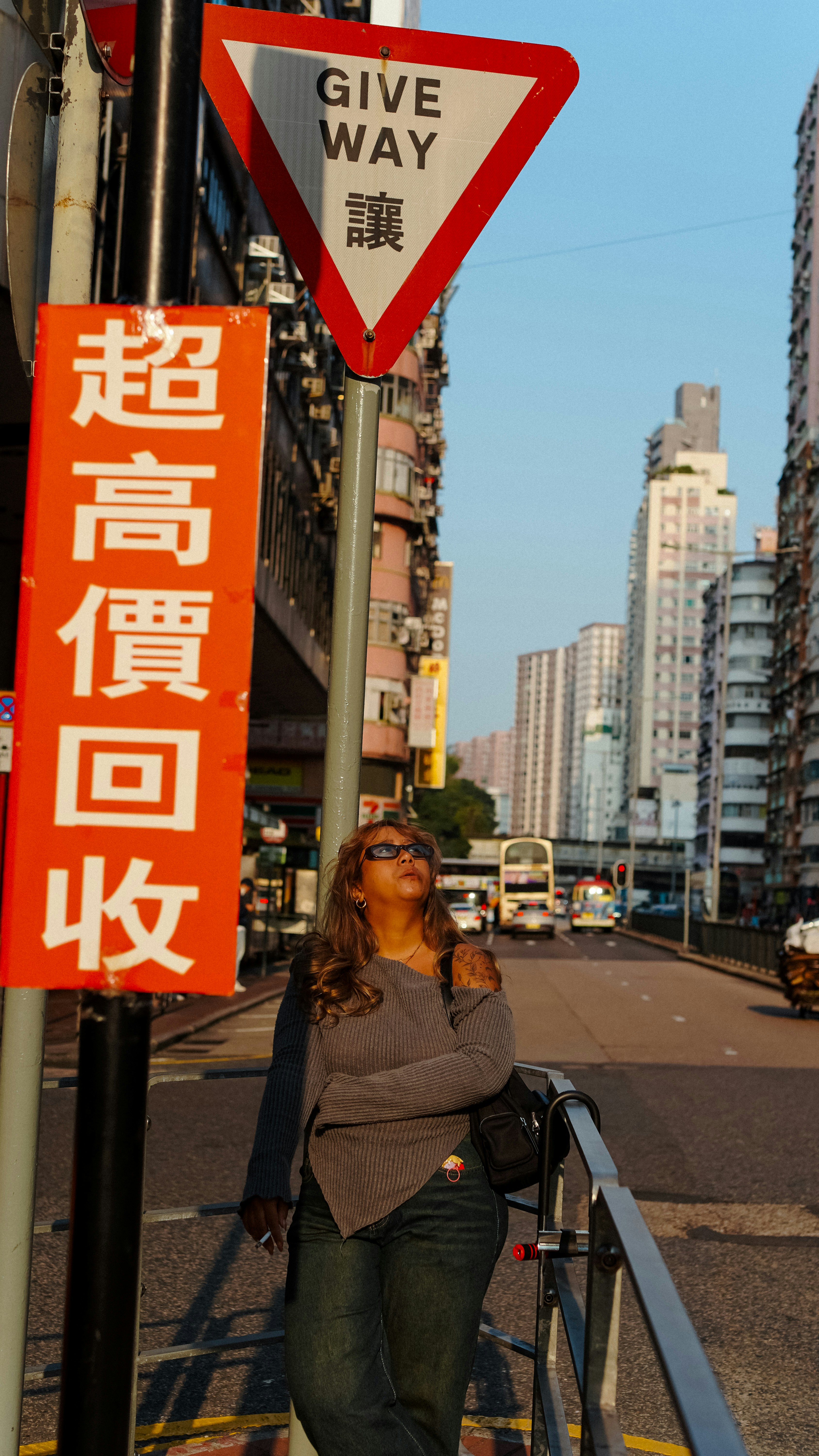 Crosswalk Style: A Woman in Sunglasses Beneath a 'Give Way' Sign