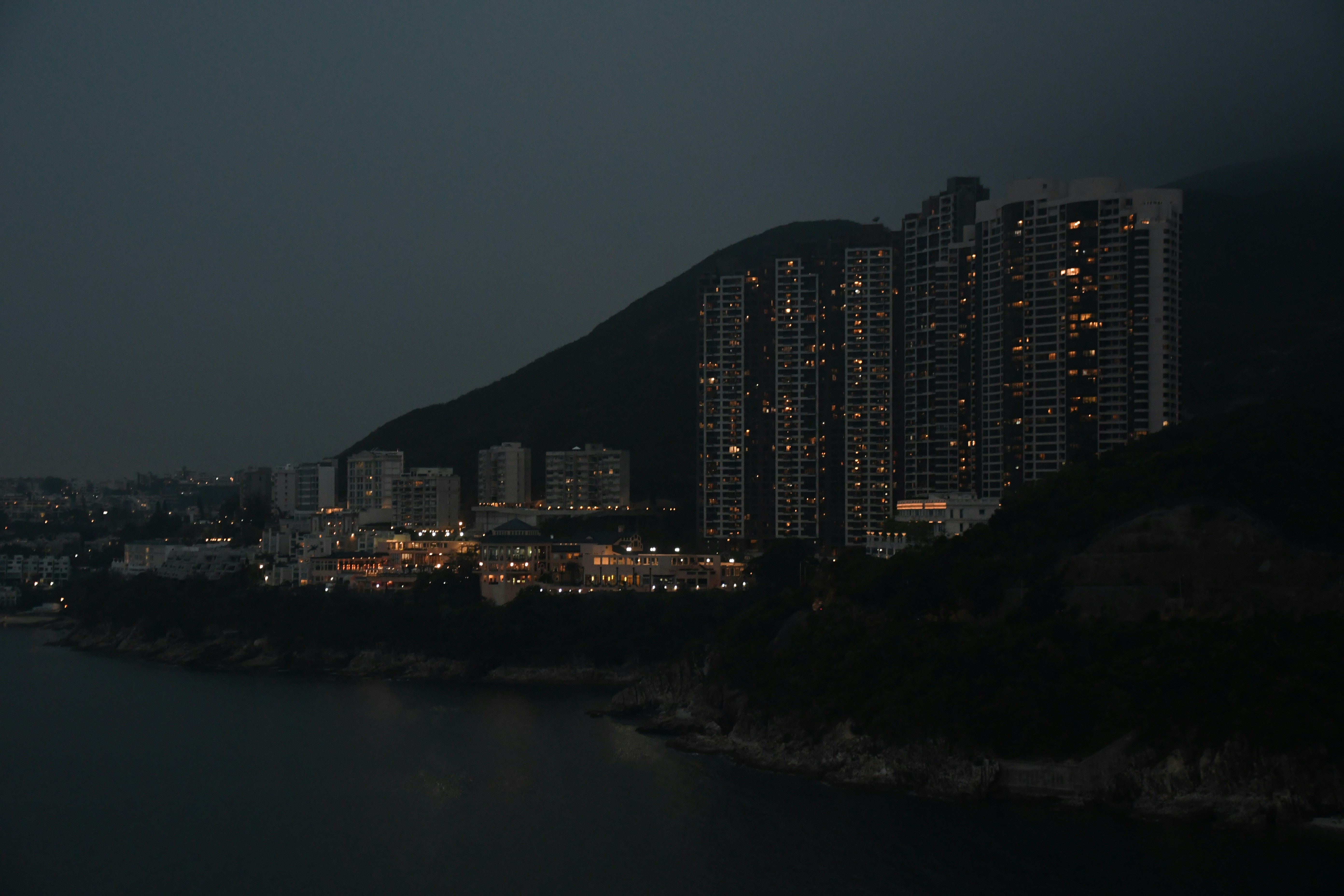 Luminous Cliffsides: Nightscape of Distant Towers Beside the Quiet Sea