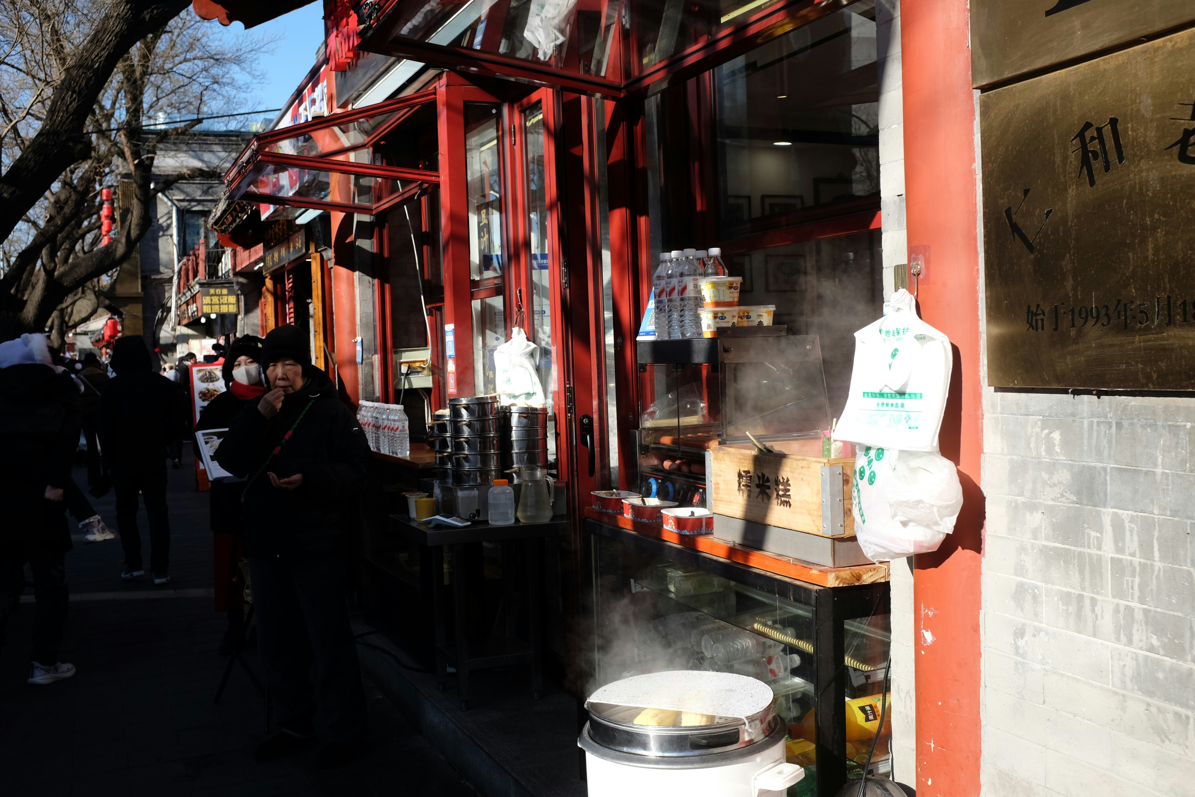 Street vendor steam with red storefronts under Chinese temple facade