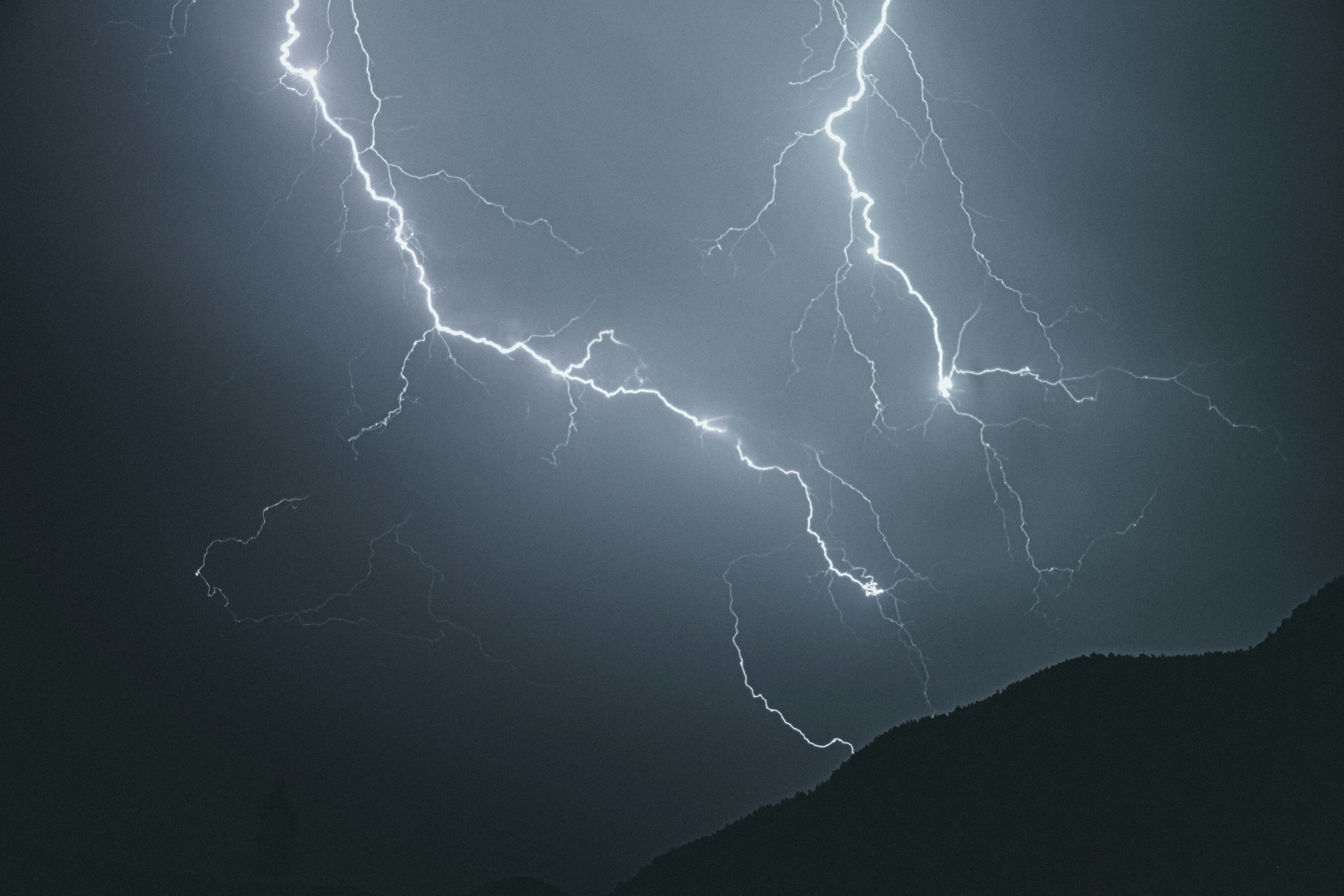 Midnight Surge: a jagged bolt carving the storm over a silhouetted ridge