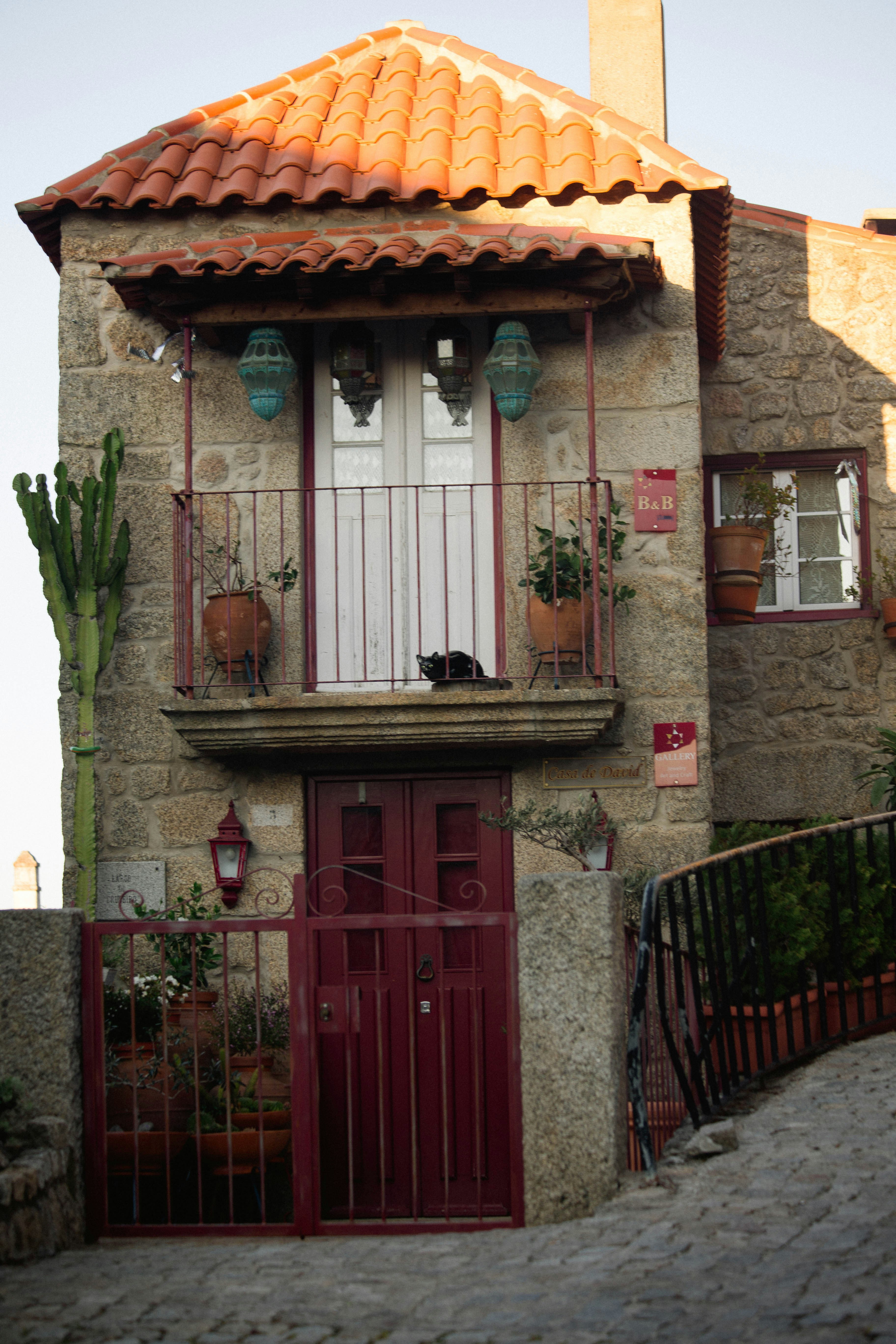 Terracotta Roof, Red Gate: A Winding Path to a Stone Balcony