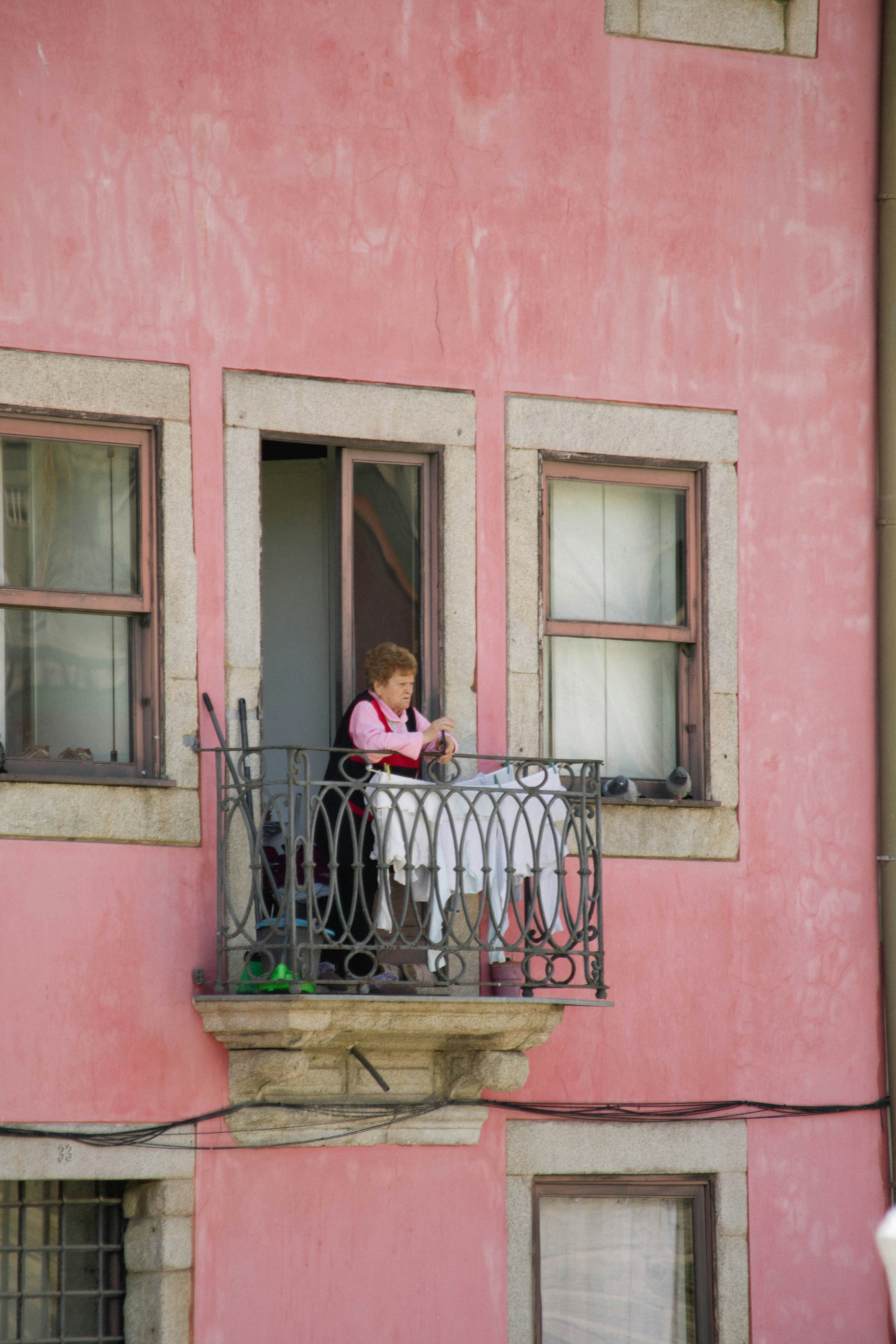 Balcony Quiet: A Woman at the Pink Facade