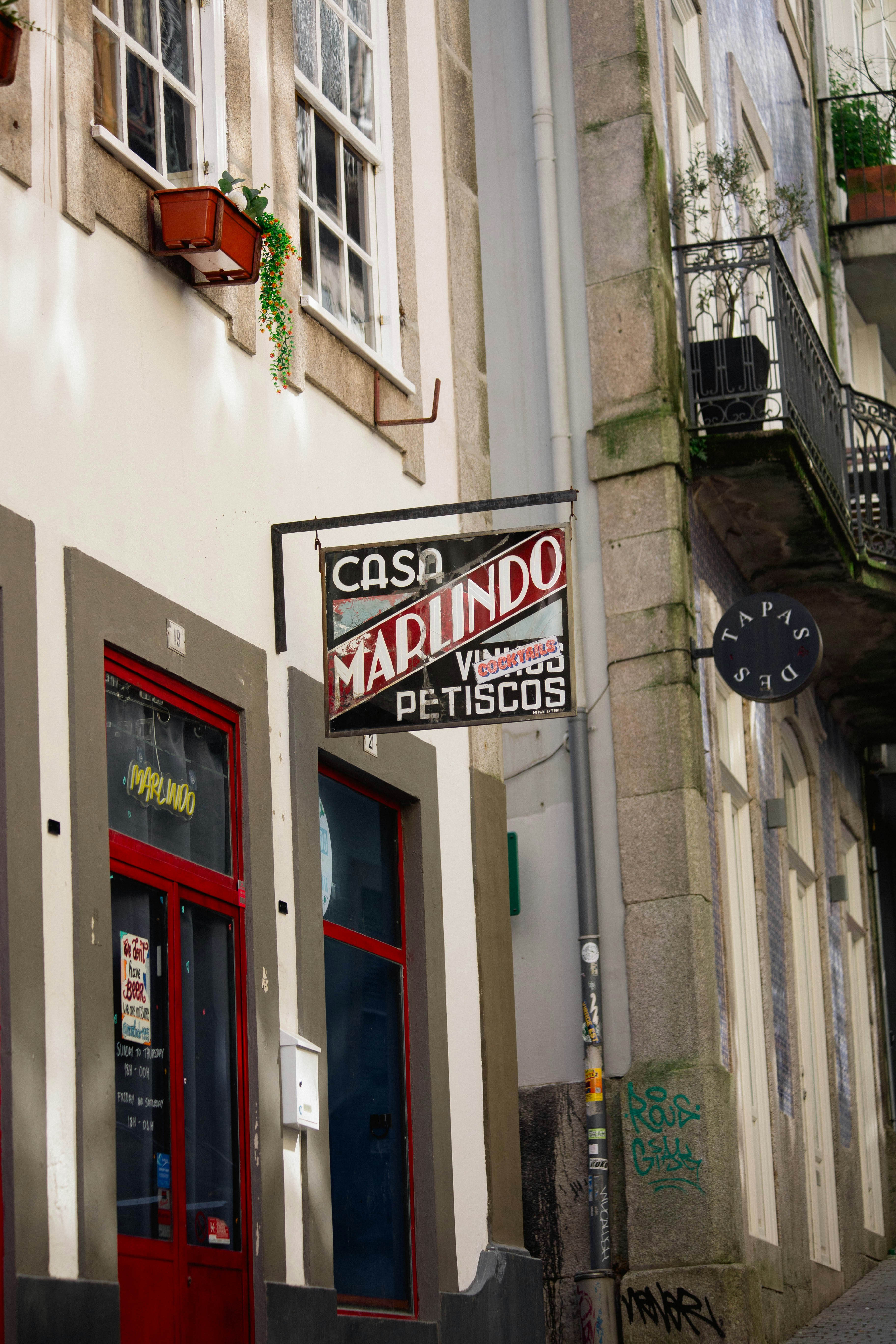Charred Red Doors and Hanging Sign: A Street-Level Corner of a Portuguese-Filled Facade