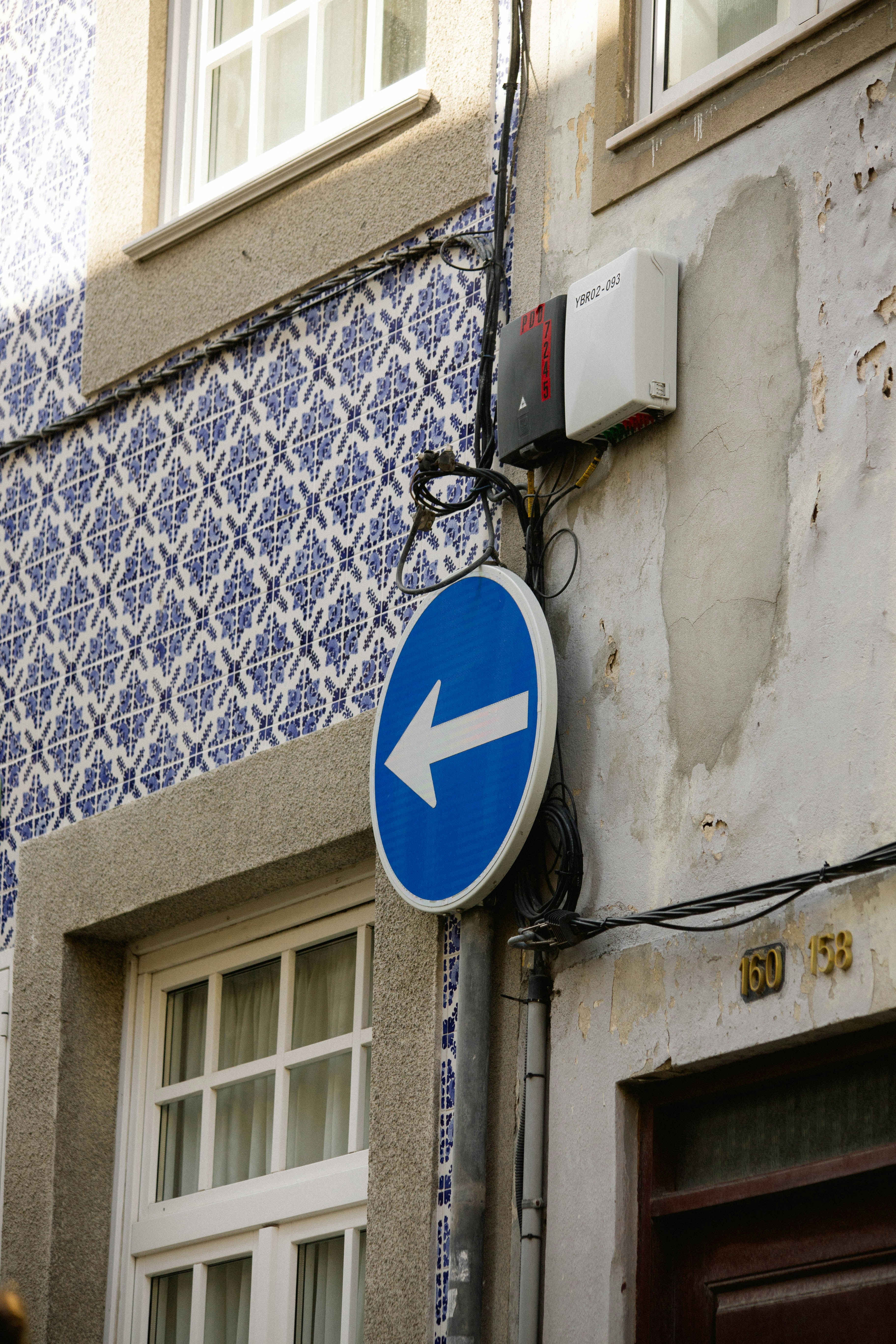 Blue Arrow: A Narrow Street Sign Against Weathered Facades