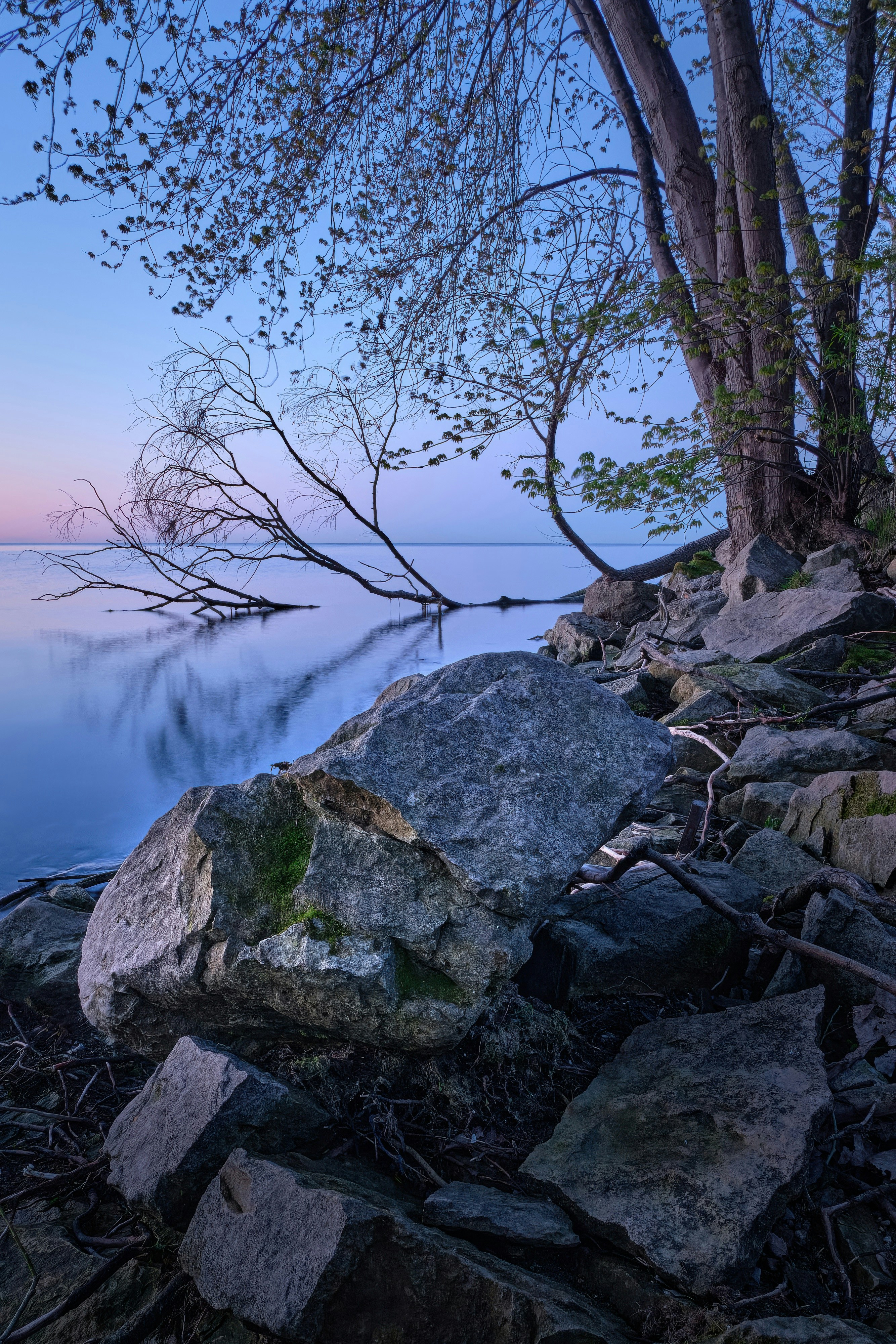 Silent shoreline at dusk: a haphazard jumble of boulders by the water