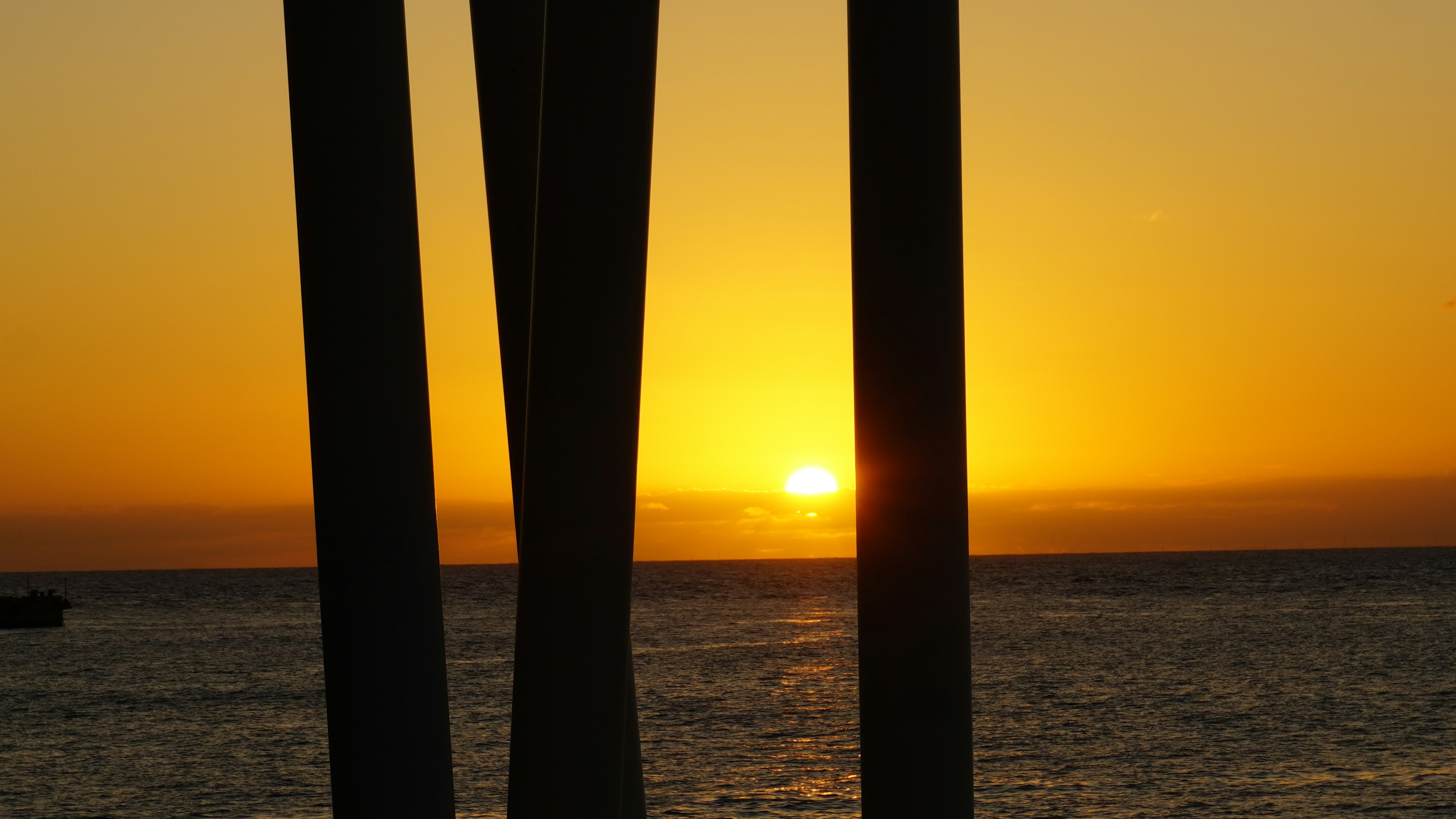 Silhouetted Columns at Sunset over a Calm Sea