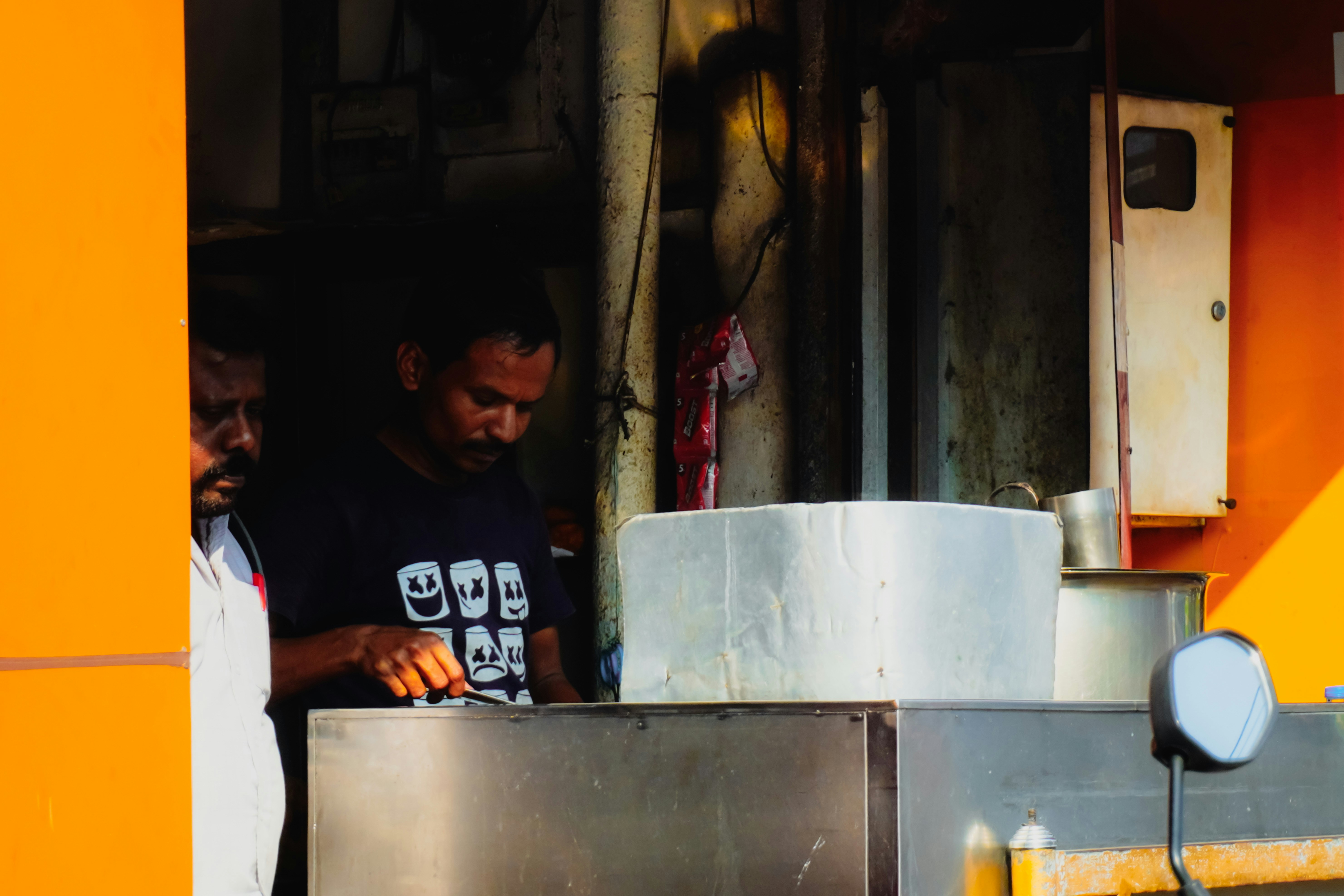 Hands at Work in the Steam Kitchen Behind Bright Orange Panels