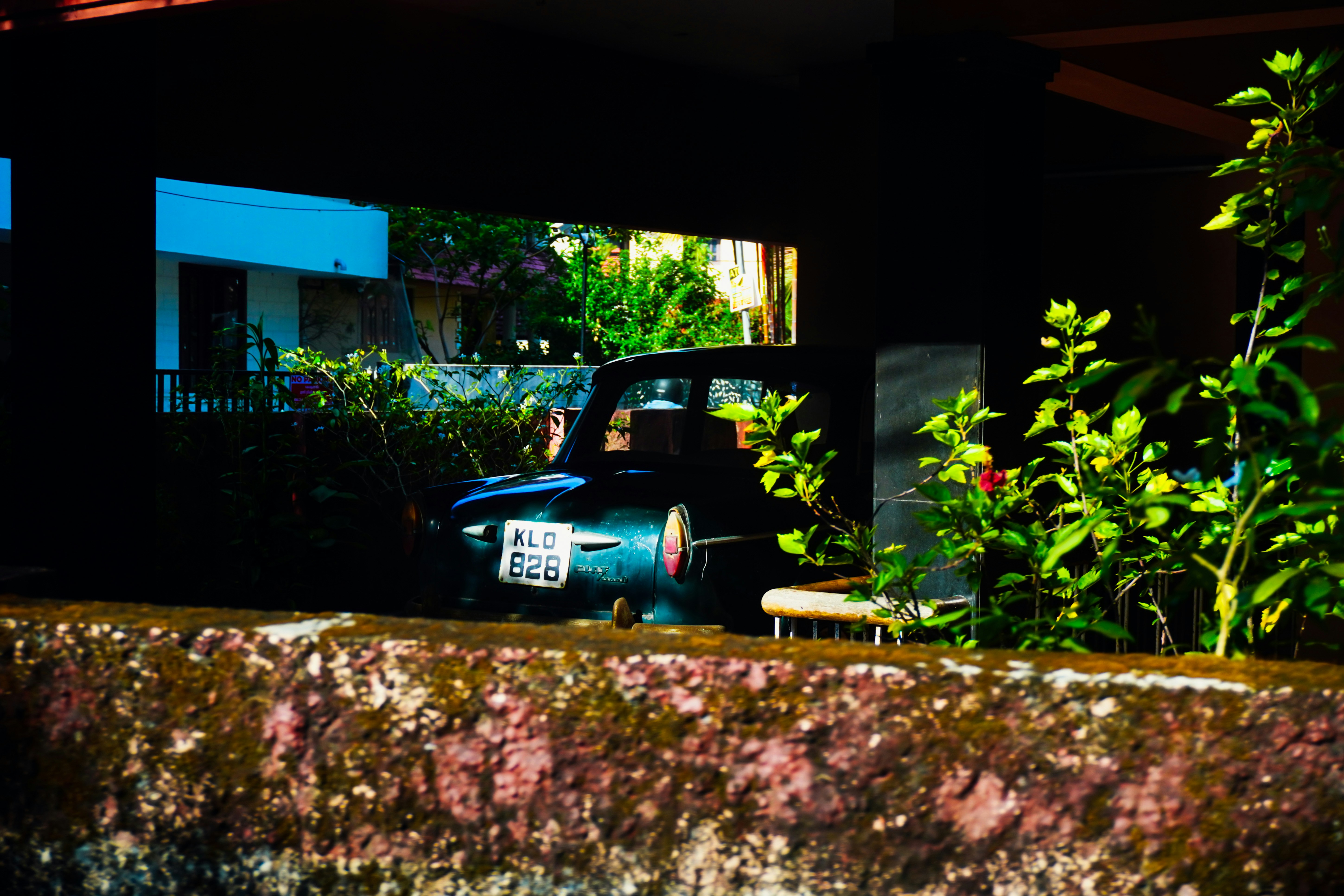 Hidden Classic: A Vintage Car Resting Under a Sunlit Archive
