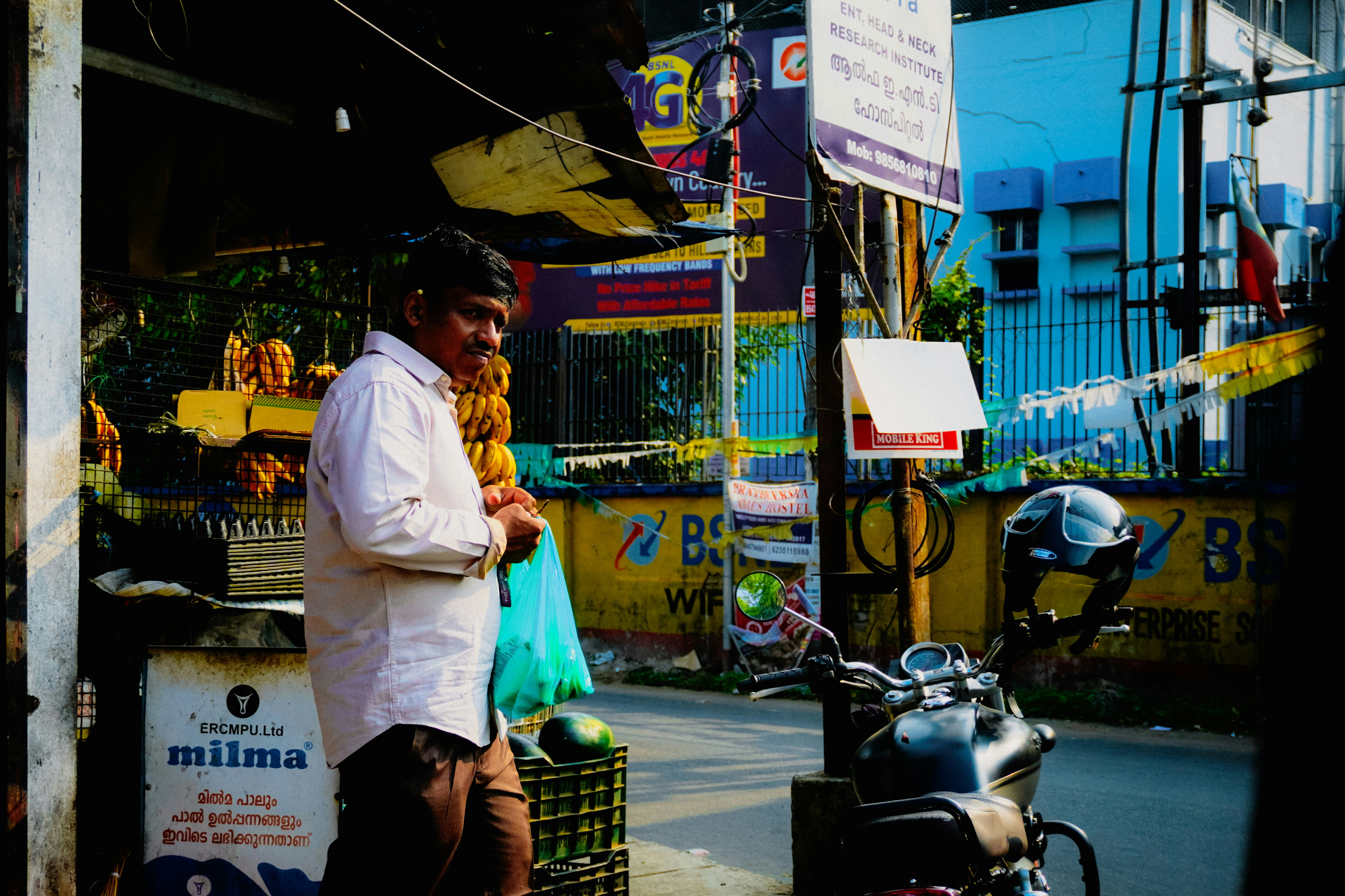 Market Scene: A Vendor in White Shirt with Banana Stall by a Busy Street