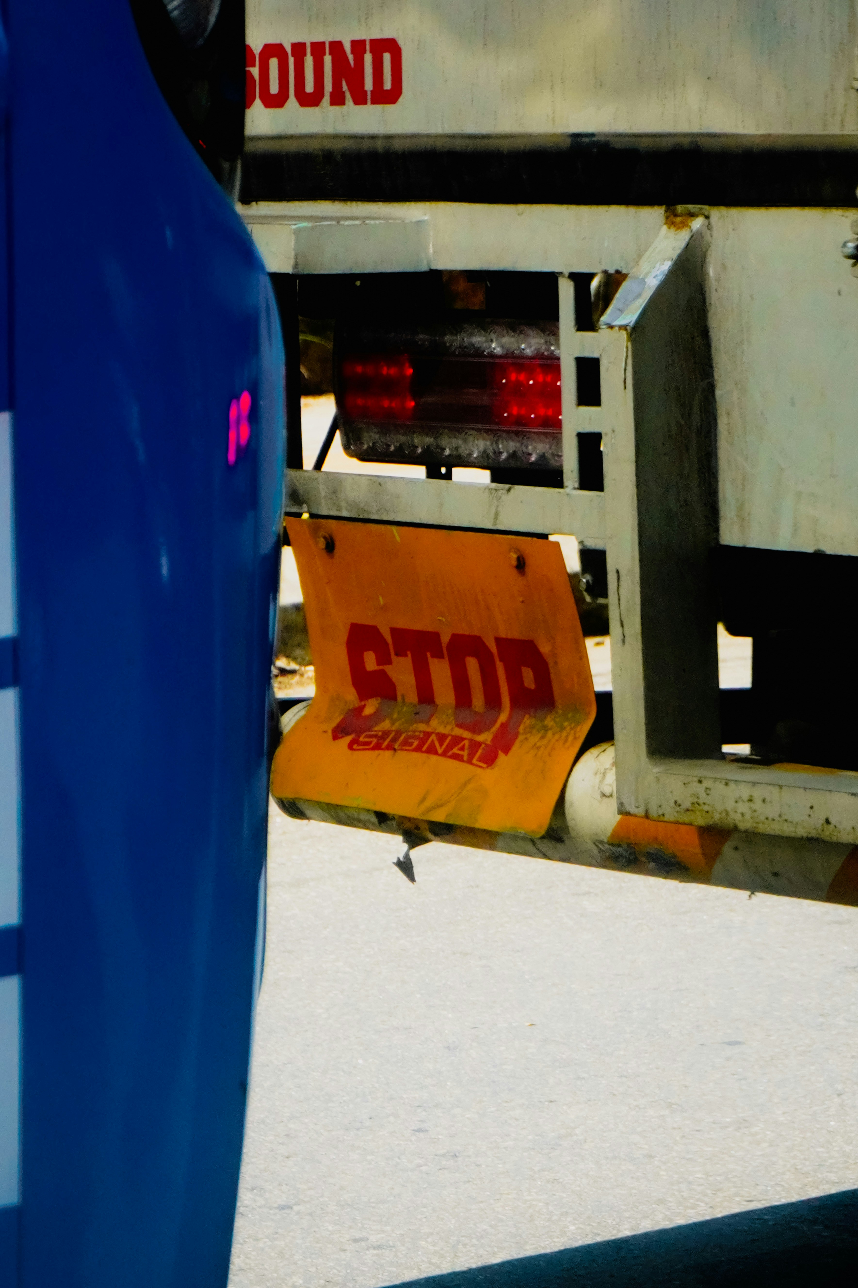 Hidden Stop Sign and Blue Vehicle Peek Behind a Backed Truck