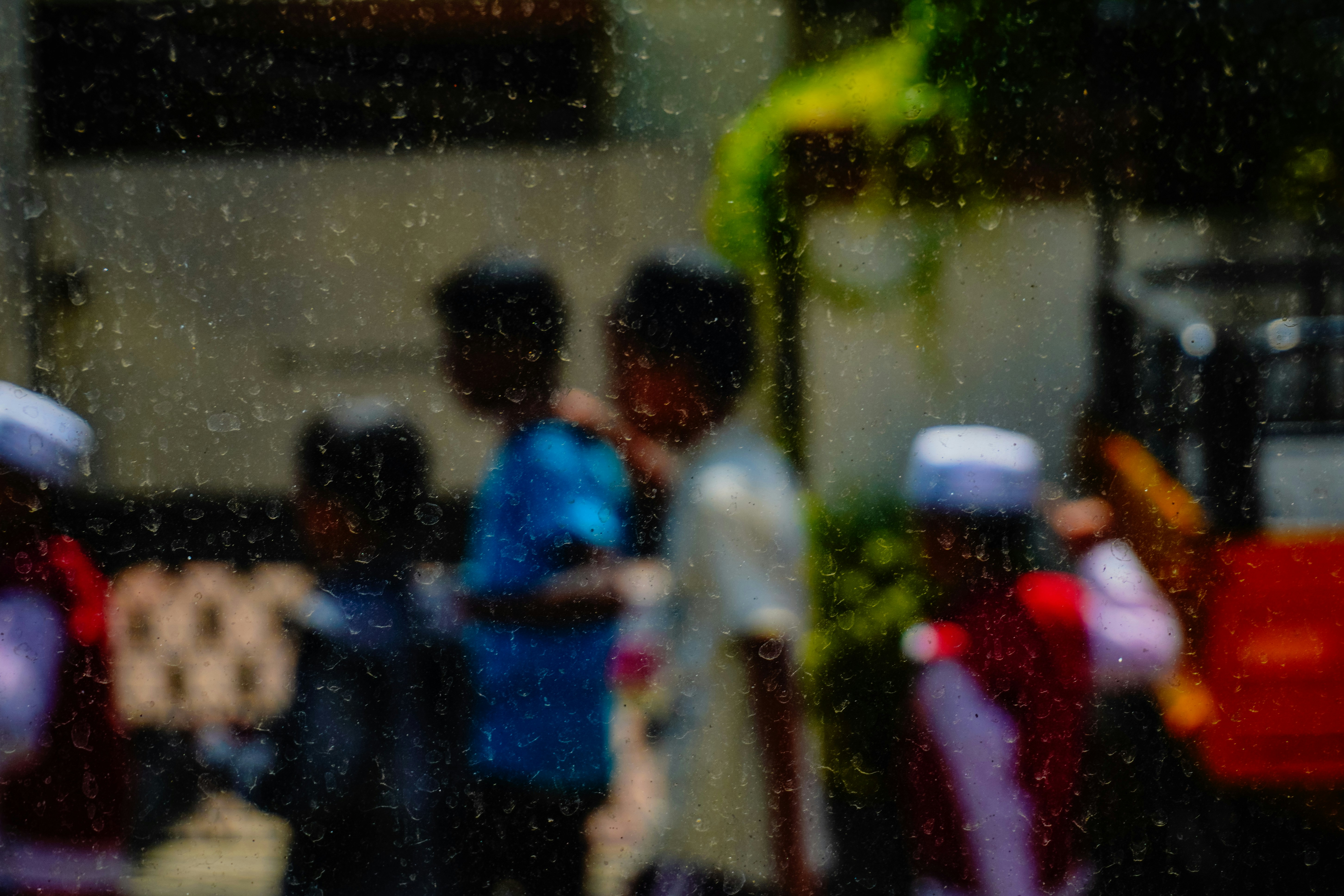 Blurred Crowd Under Rain: Faces and Colors Met by Droplets