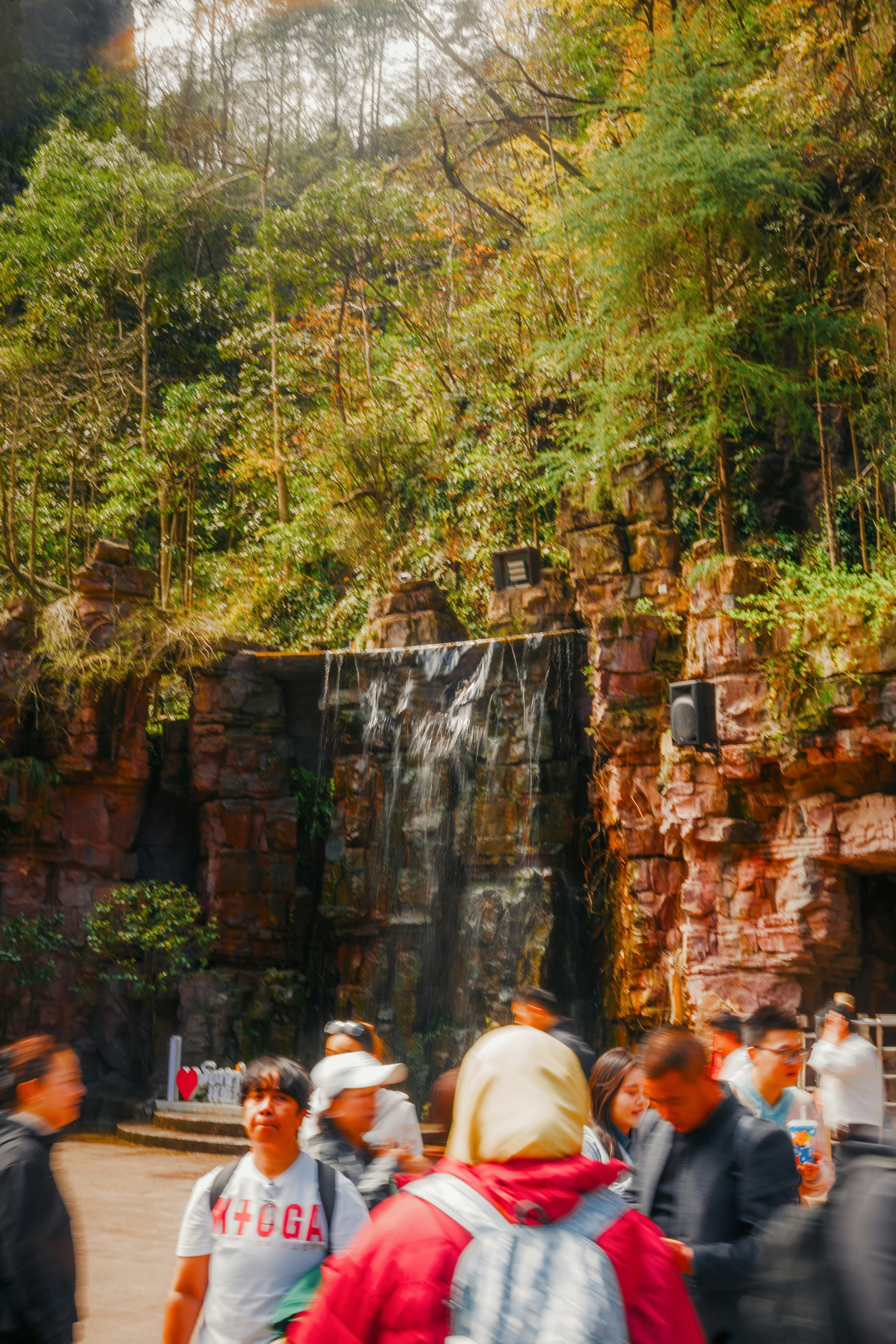 Waterfall at a crowded park: autumn colors and rushing water behind a group of visitors