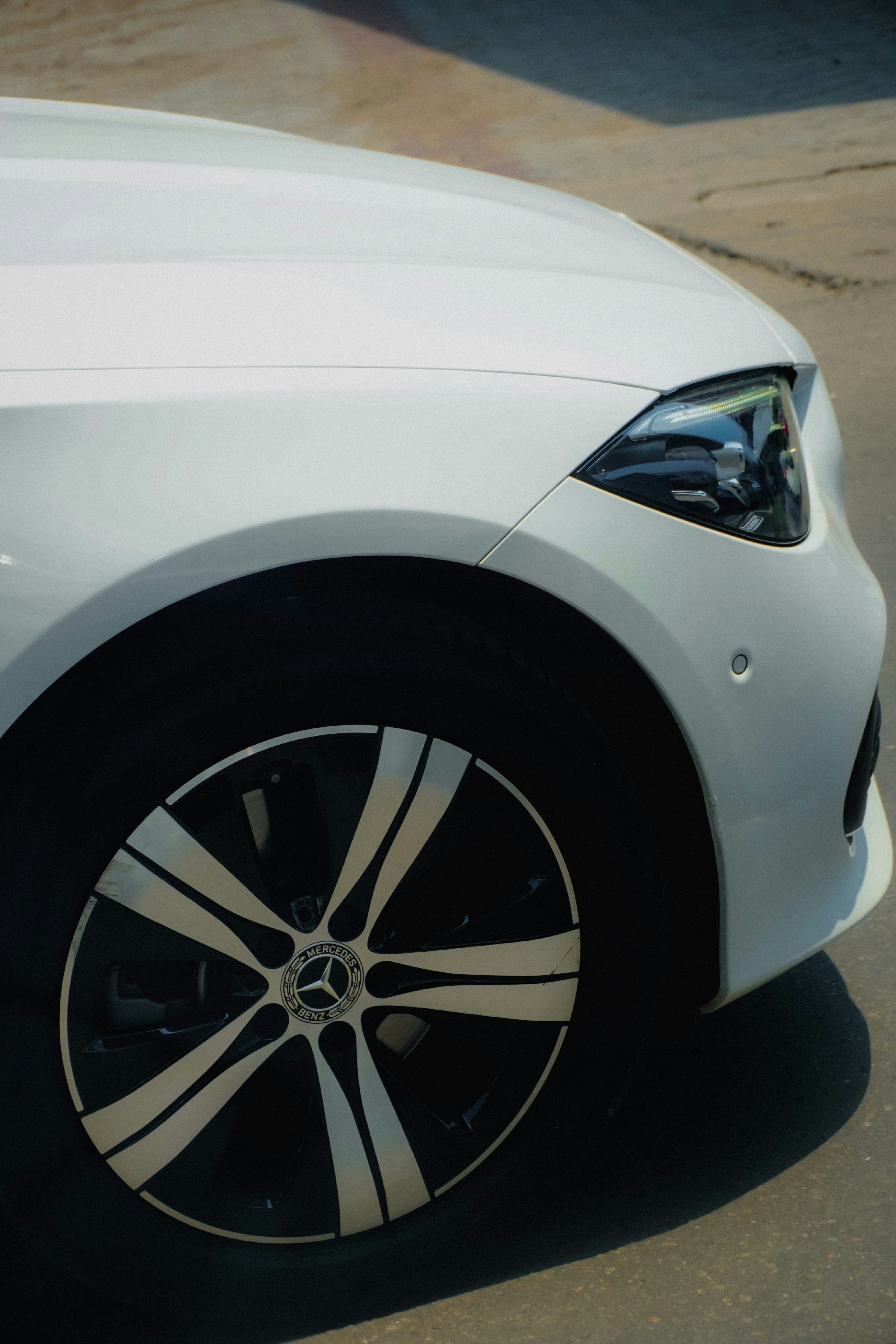 White Mercedes at the Edge: A Close-Up of the Front Wheel and Headlight