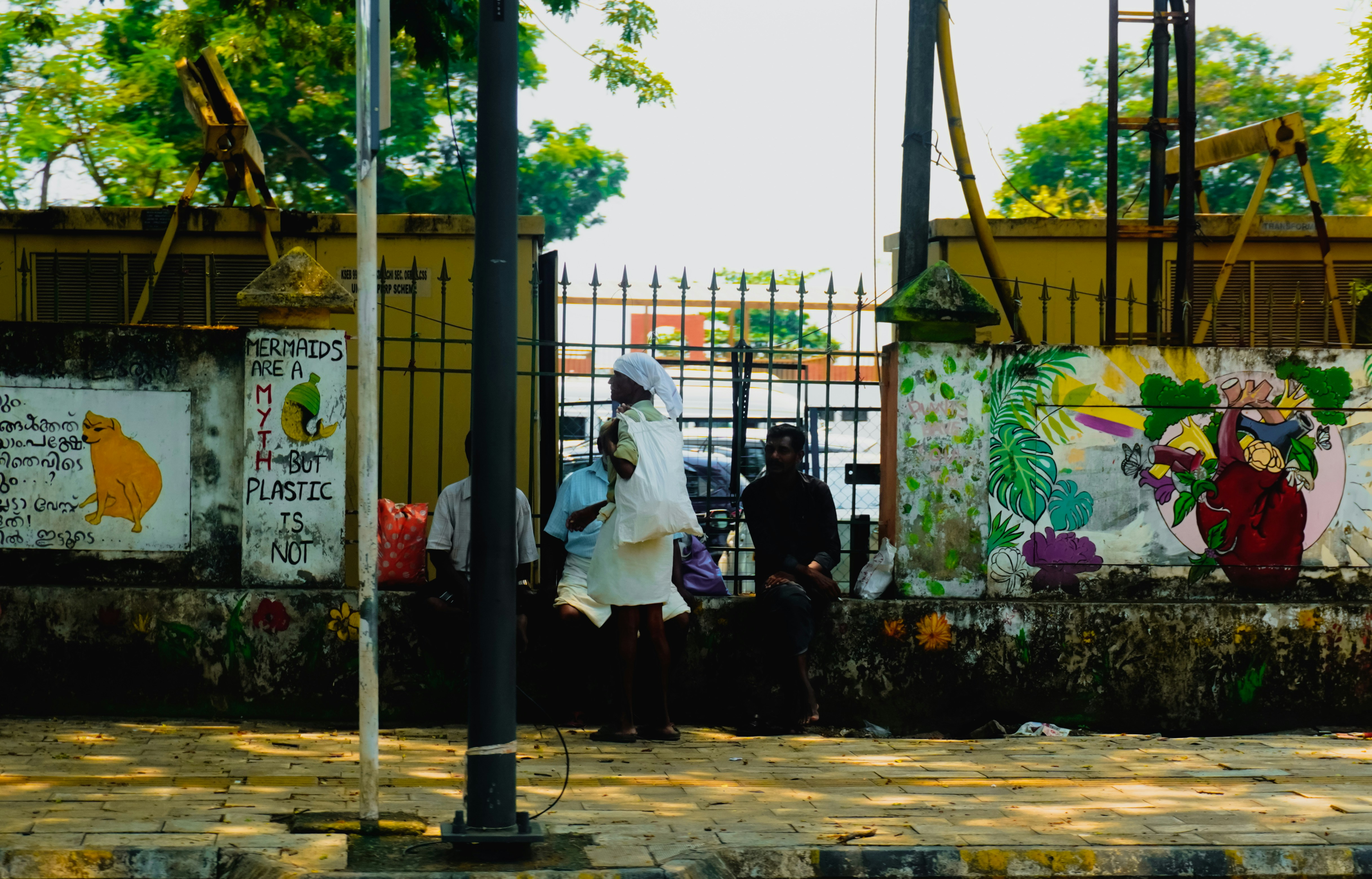Beside the Wall: Quiet Figures and Street Art in Dappled Shade