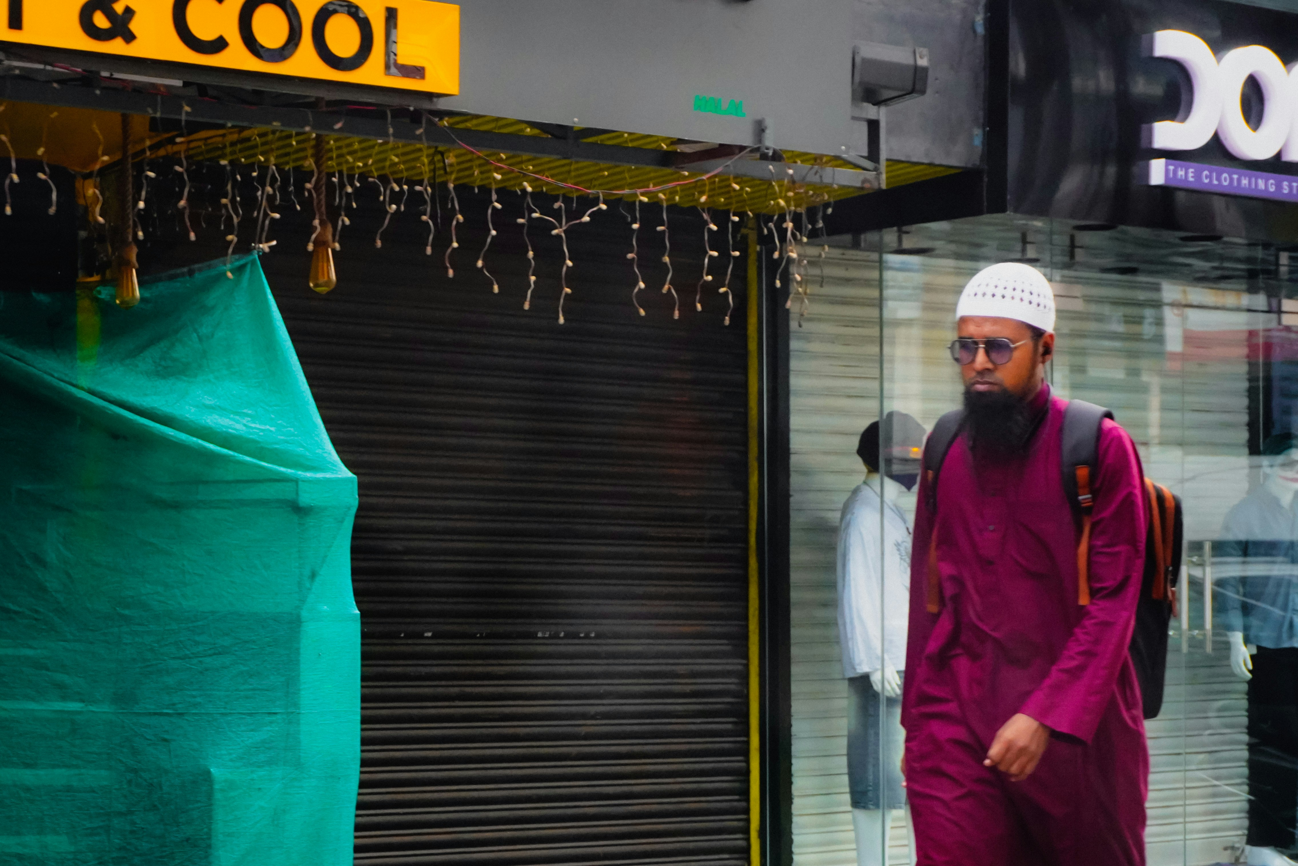 A Quiet Moment on a Busy Street: Man in Magenta Amid Closed Shops
