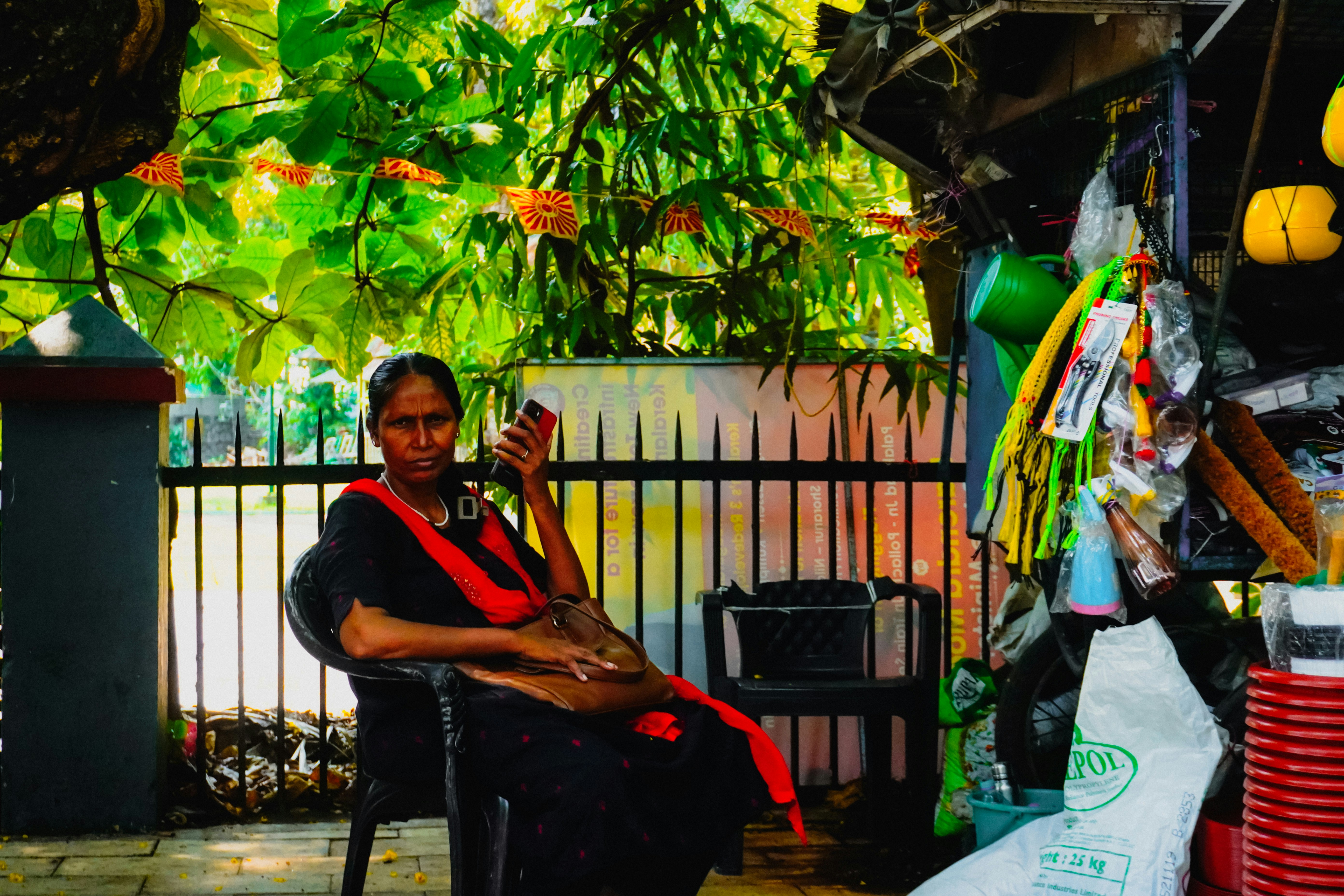 Woman in red-sashed chair under tropical canopy watching a handheld device