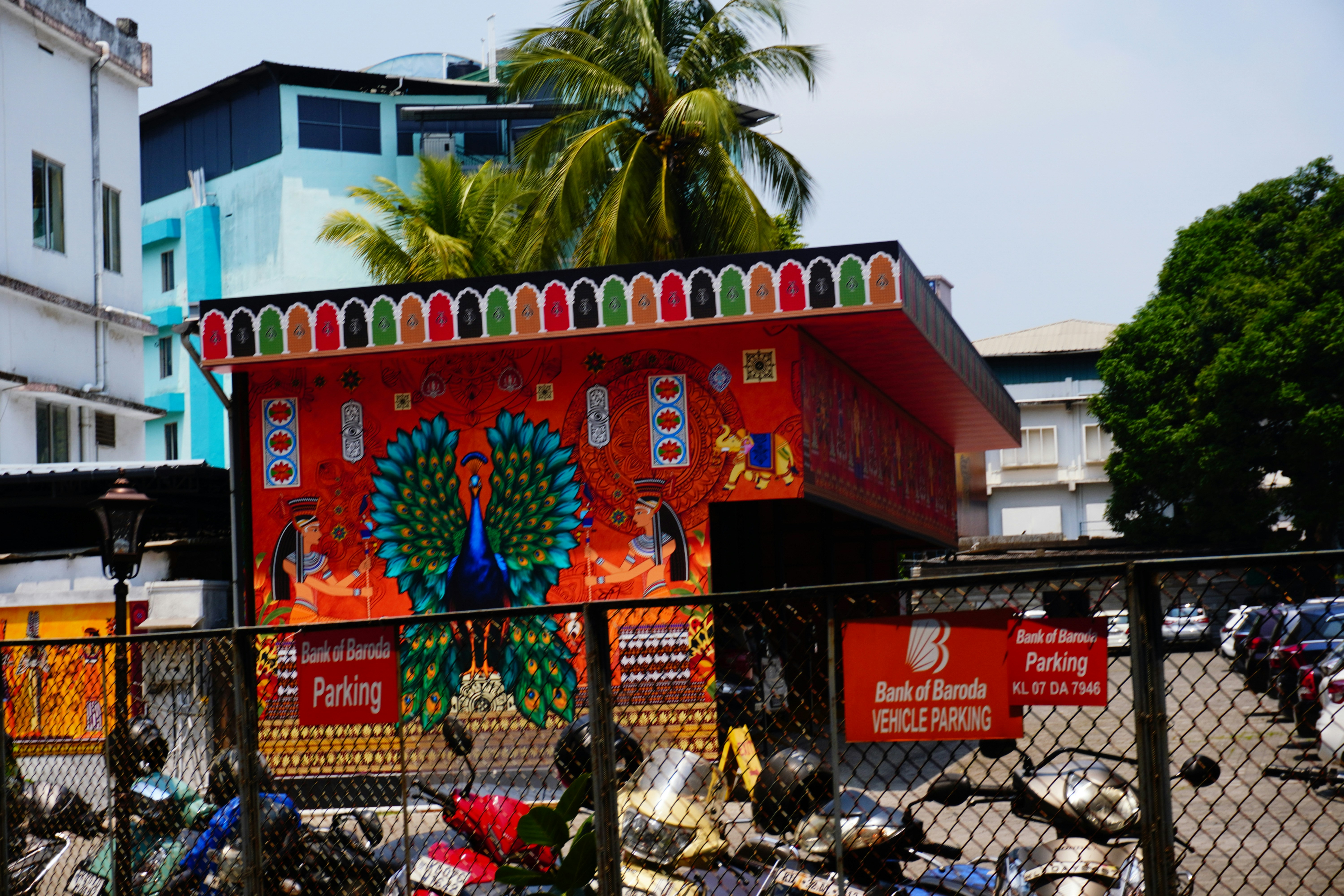 Colorful Street Booth with Peafowl Mural Fenced by Urban Parking
