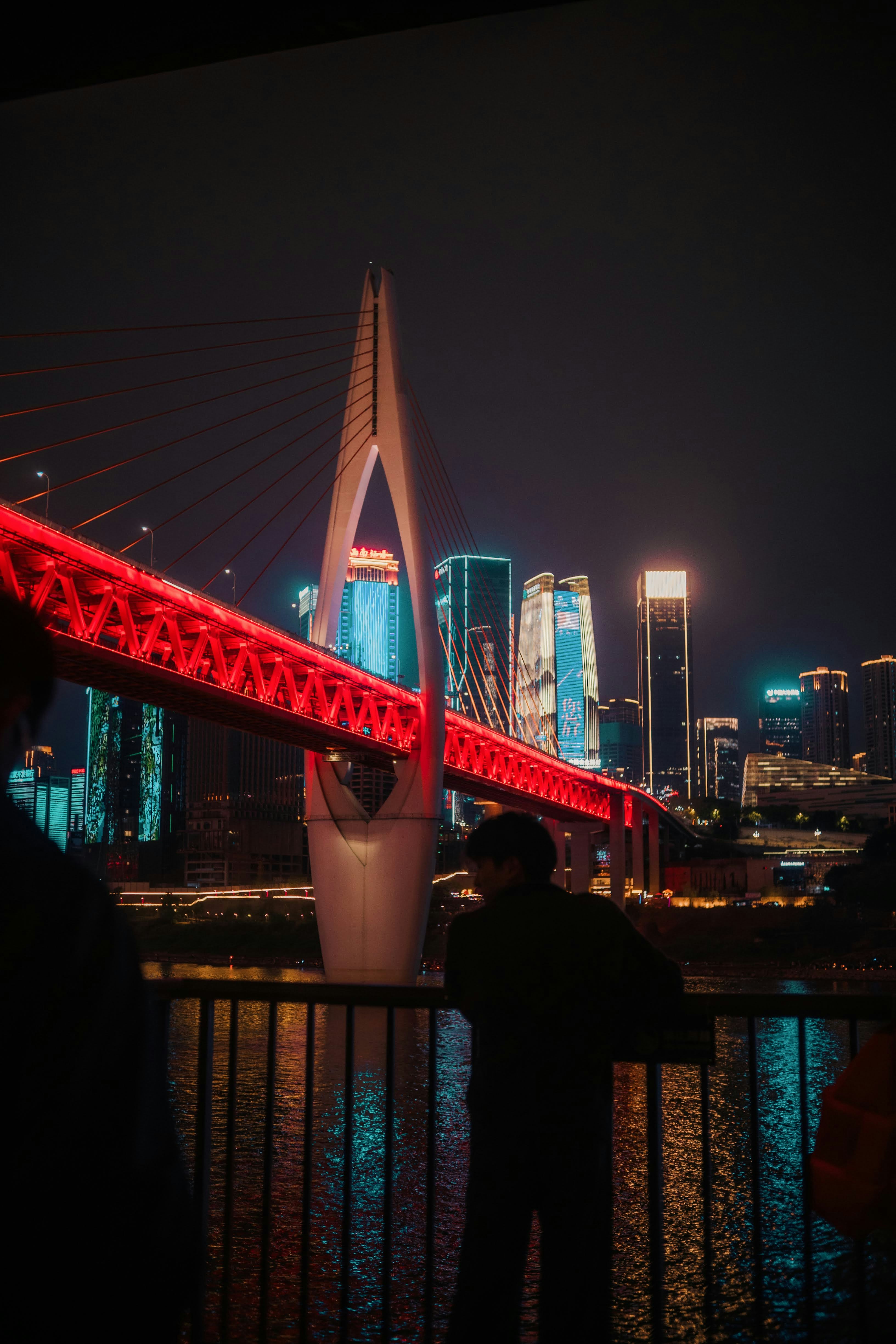 Neon River Crossing: Red Span Beneath a Sky of Skyscraper Lights