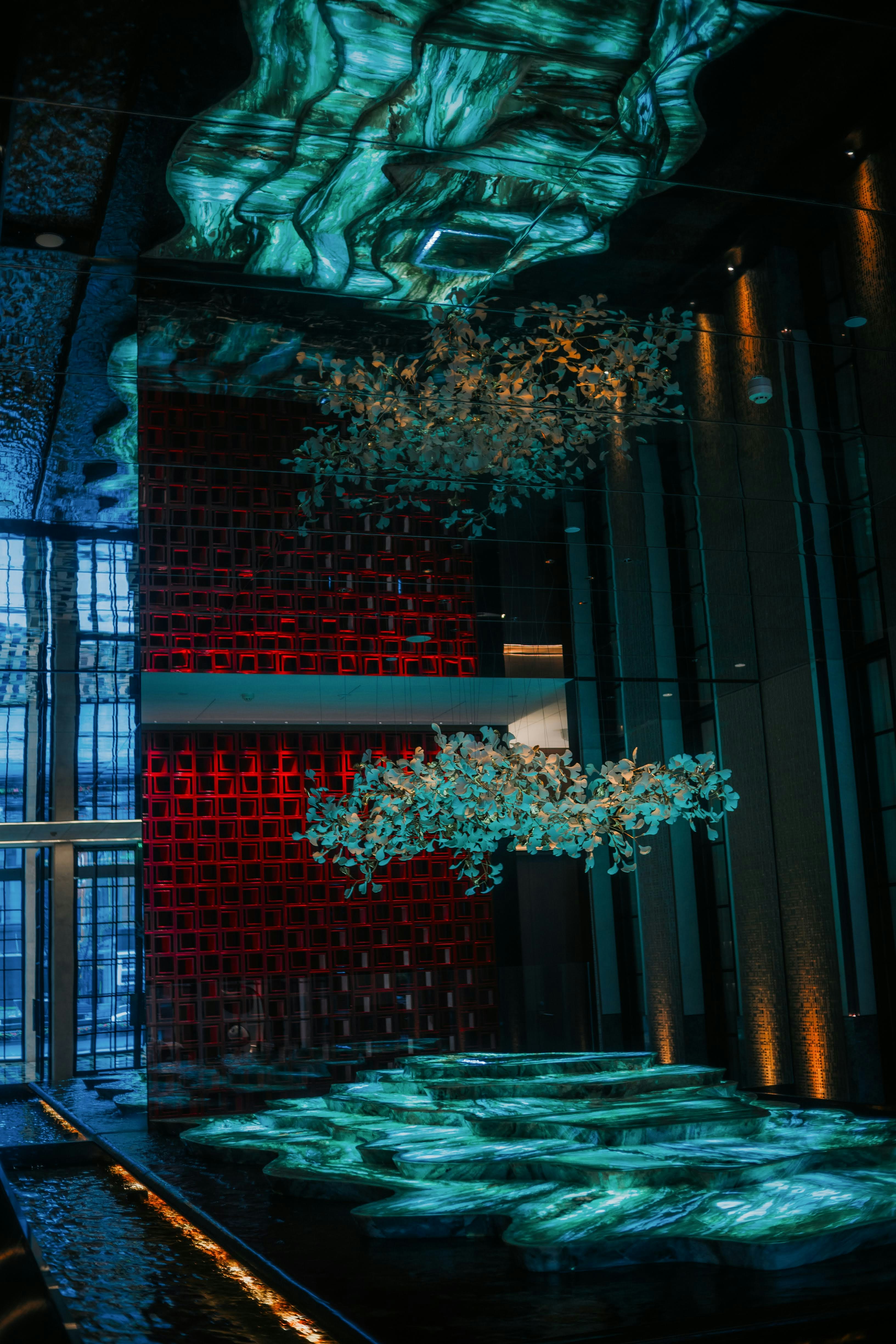 Midnight Oasis: Reflections and Red Grids in a Vertical Atrium